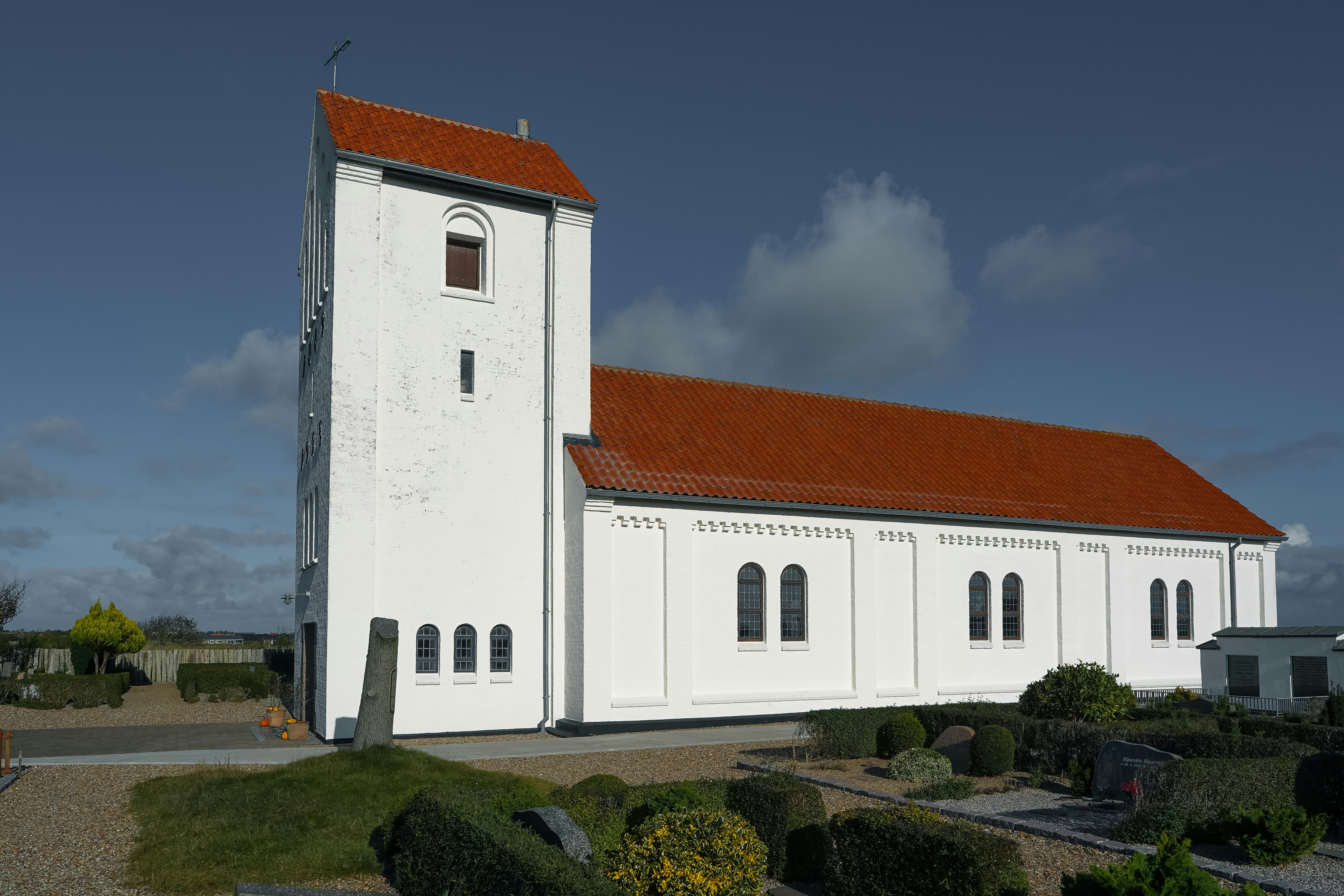 Sunlit White Church with Red Tile Roof and Quiet Garden