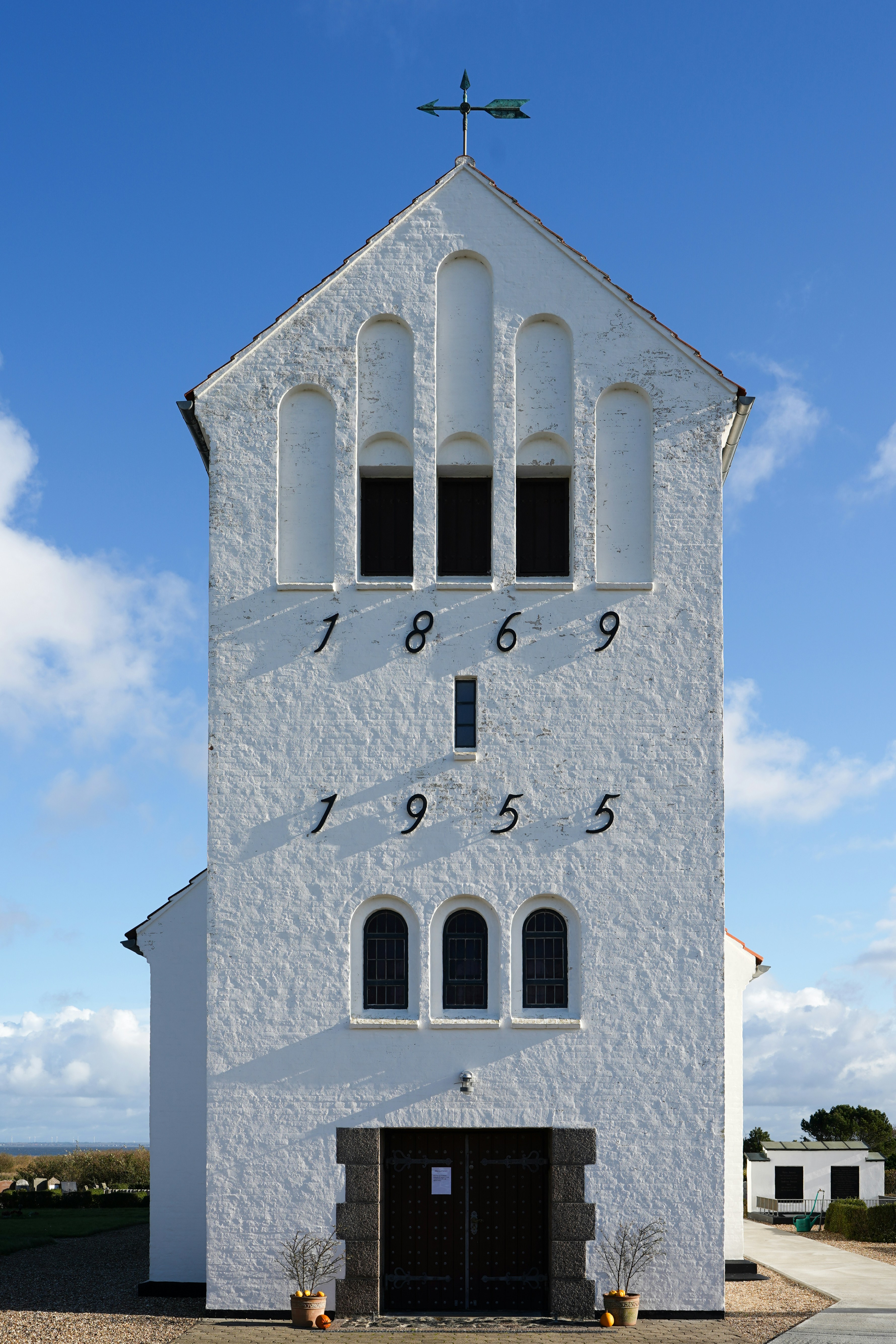 White Chapel Clock Face Surrounded by Arched Windows Under a Clear Sky