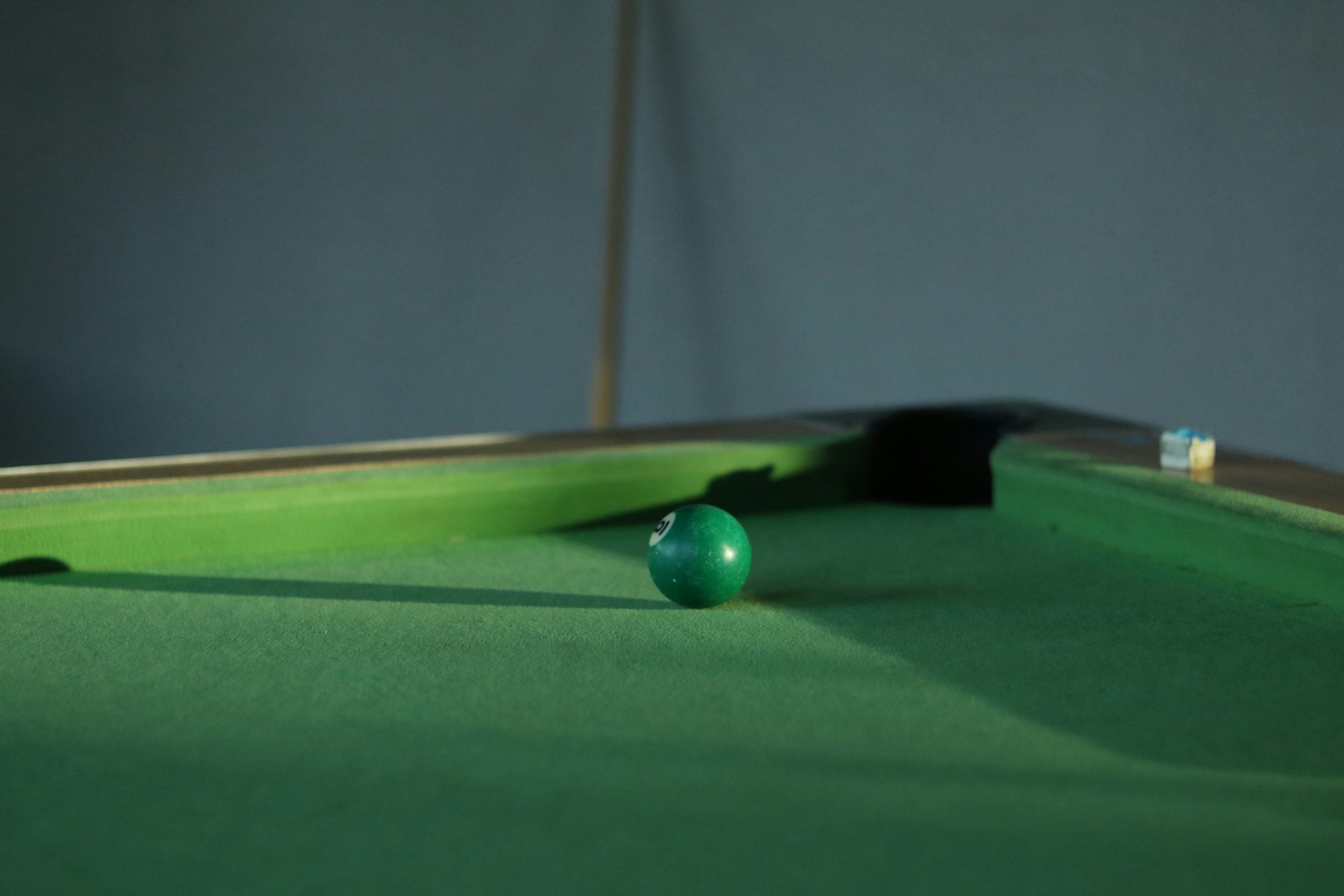 Green Ball on a Shadowed Green Felt: A Quiet Break in the Pool Hall