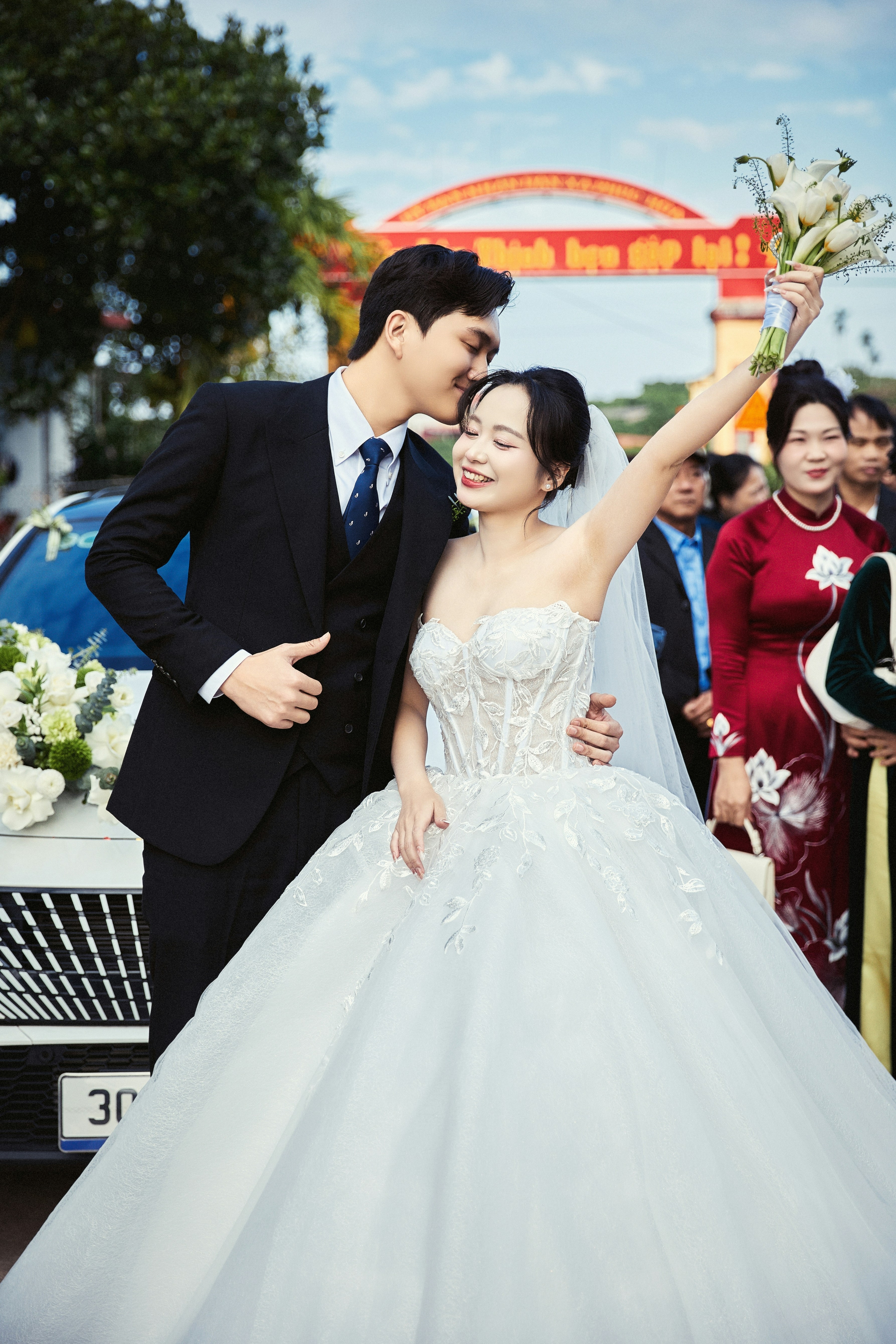 Wedding Smile: A Couple's Lift Under a Festive Arch