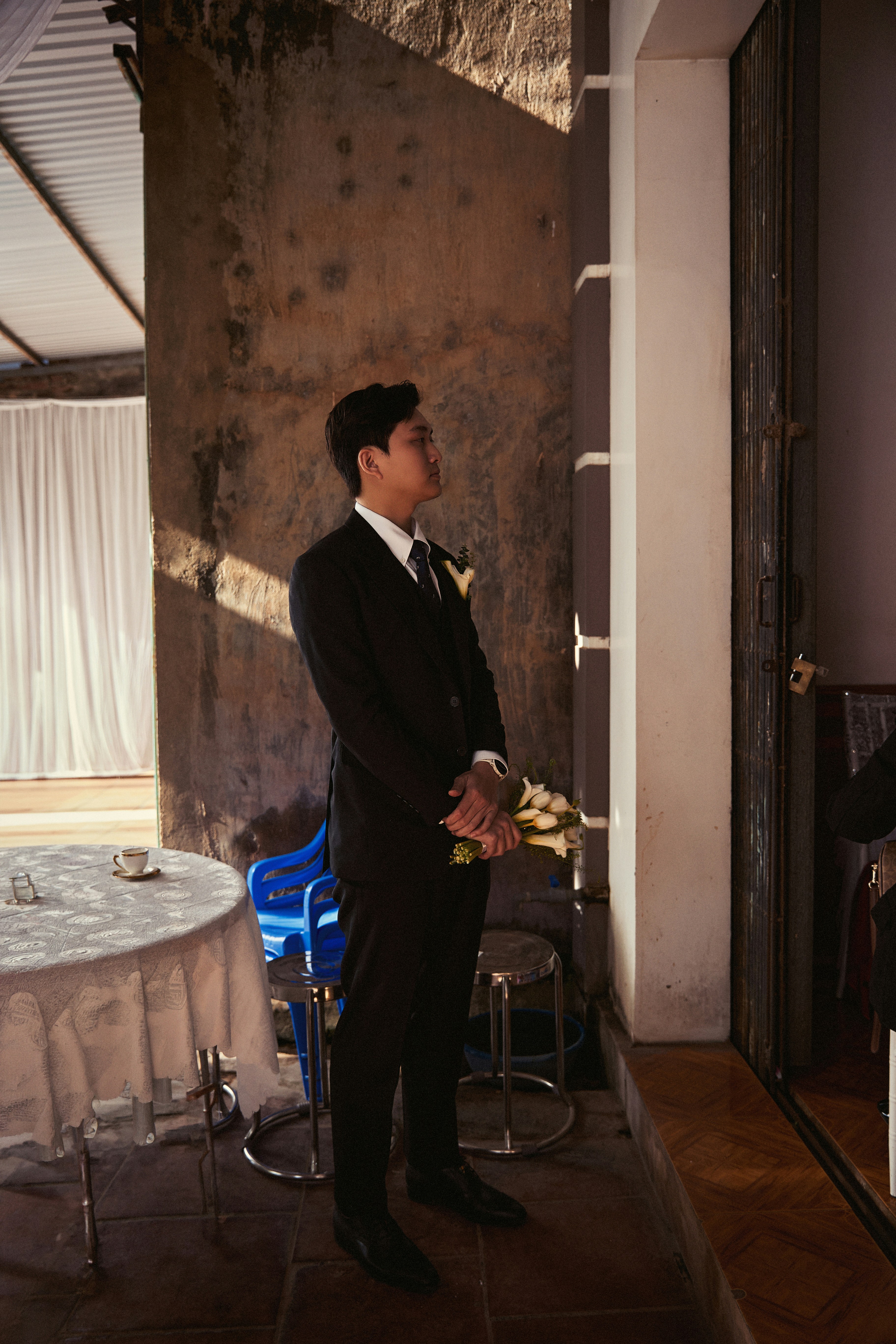 A Groom in Shadowed Hallway: Quiet Pride by the Pillar