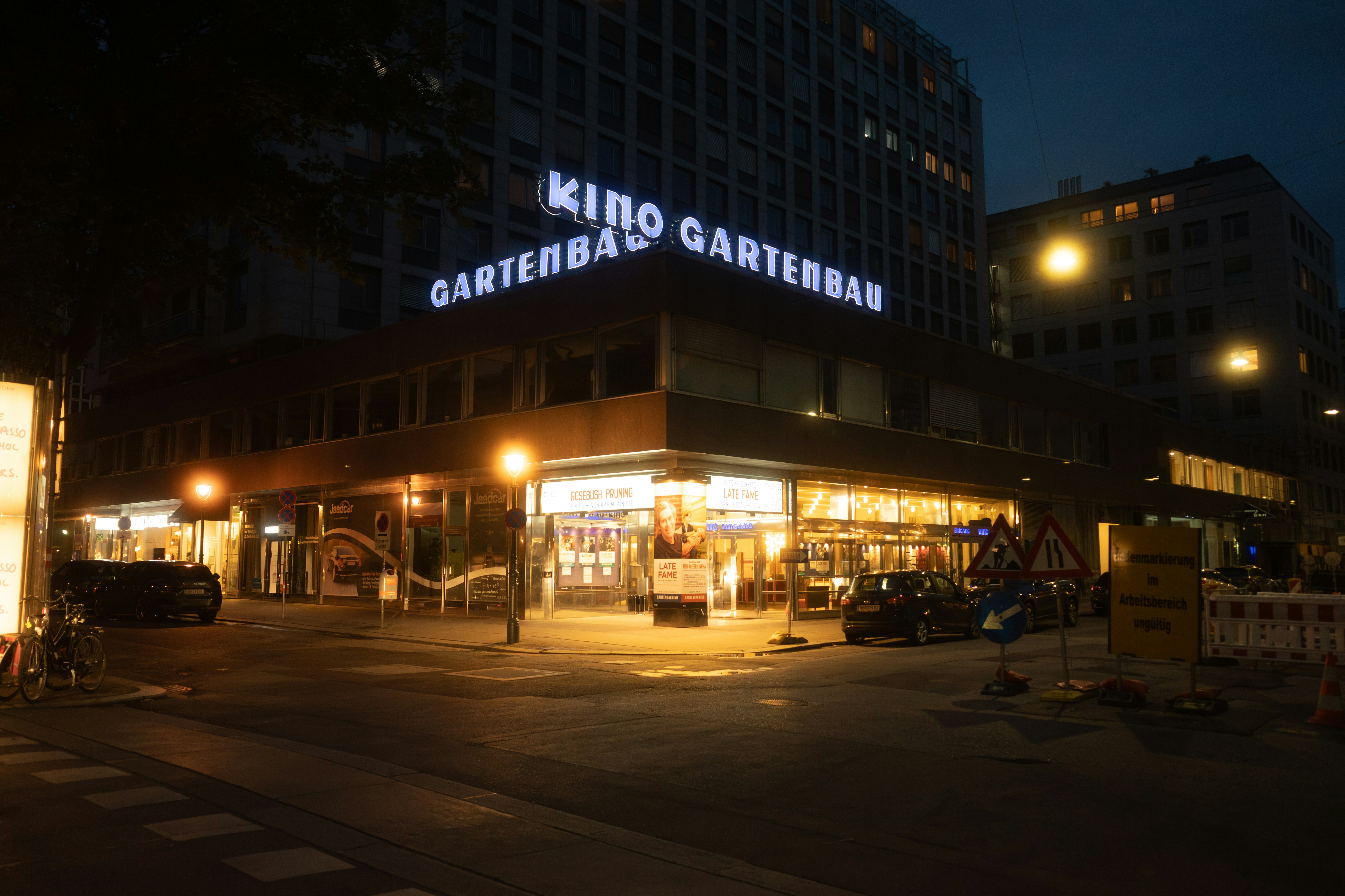 Nighttime cinema facade at a lit corner storefront
