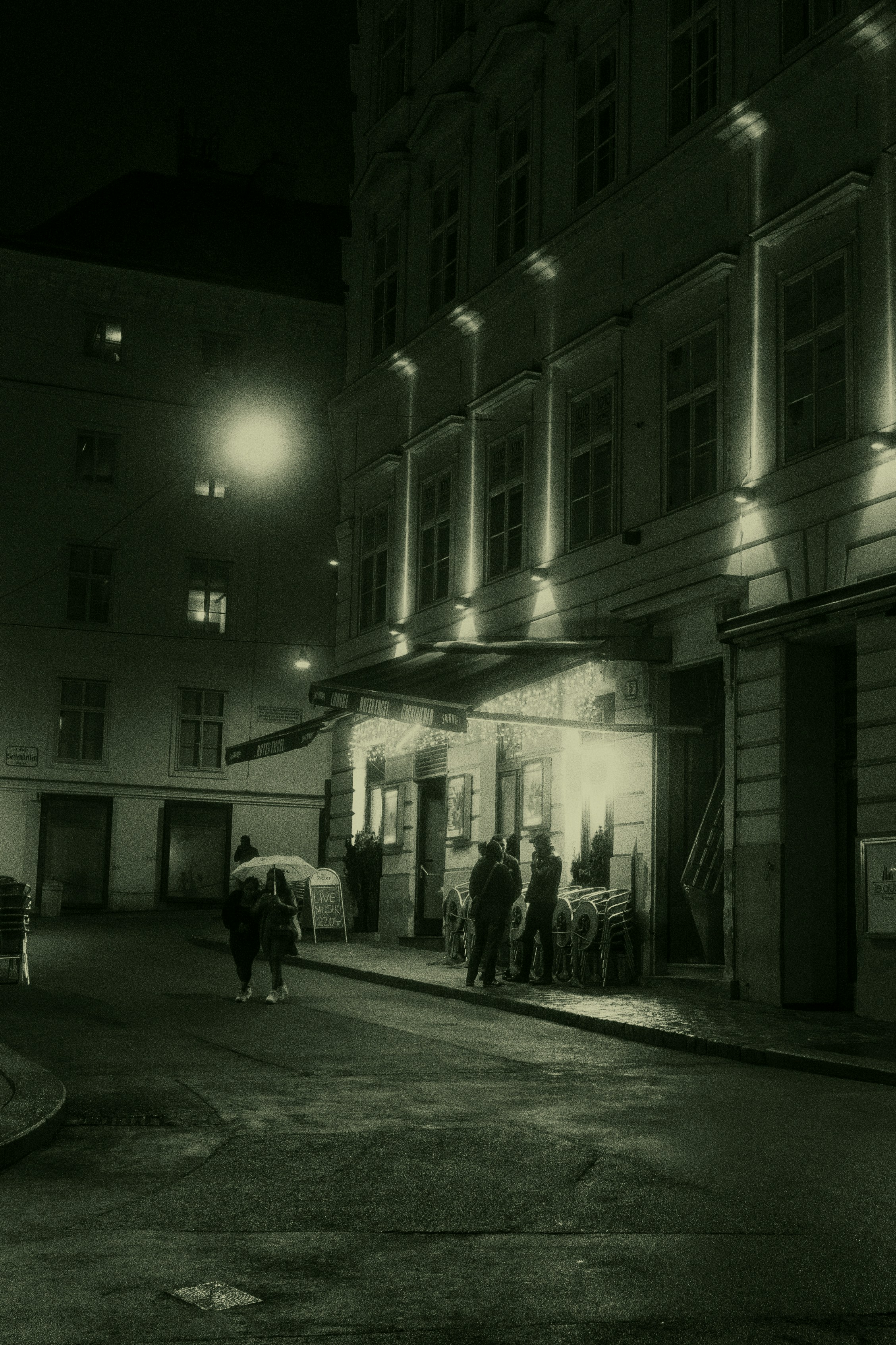 Night Entrance: Warm Light spilling onto a Quiet Cobblestone Alley