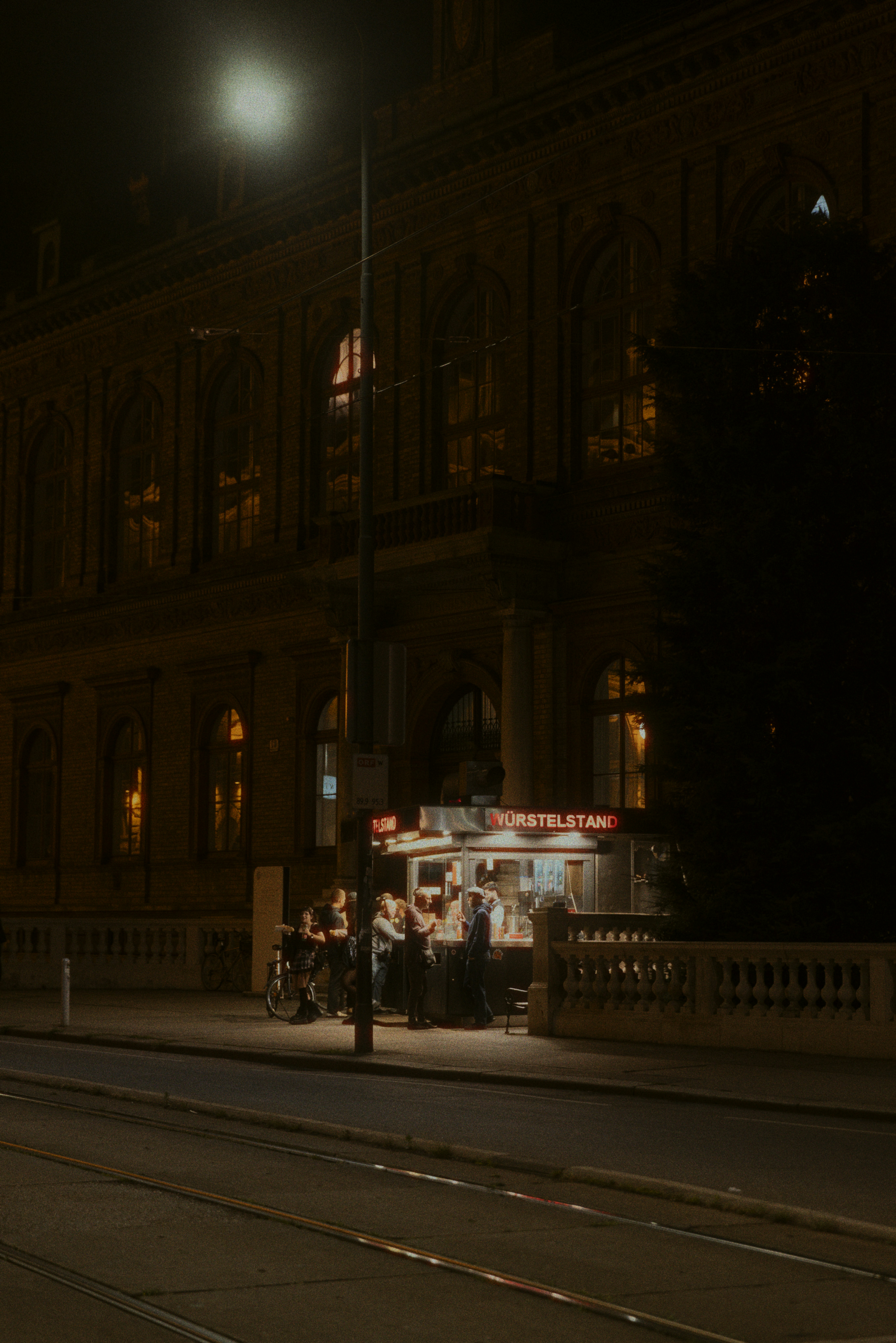 Nightstreet Cart: Warm Glow of a Food Stand Beside an Iron-Clad Facade
