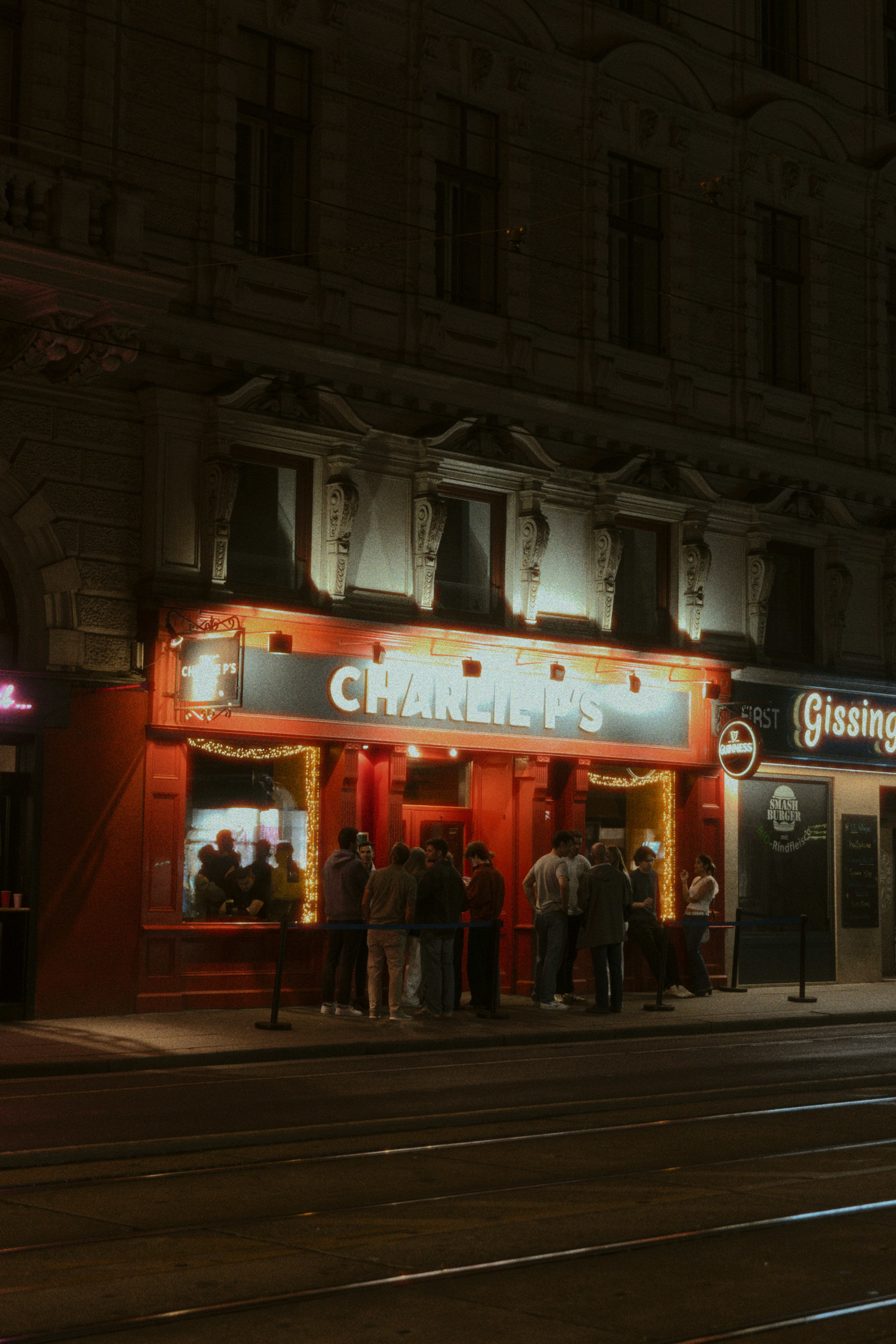 Neon Red Front: Line of Patrons at a Nighttime Barfront