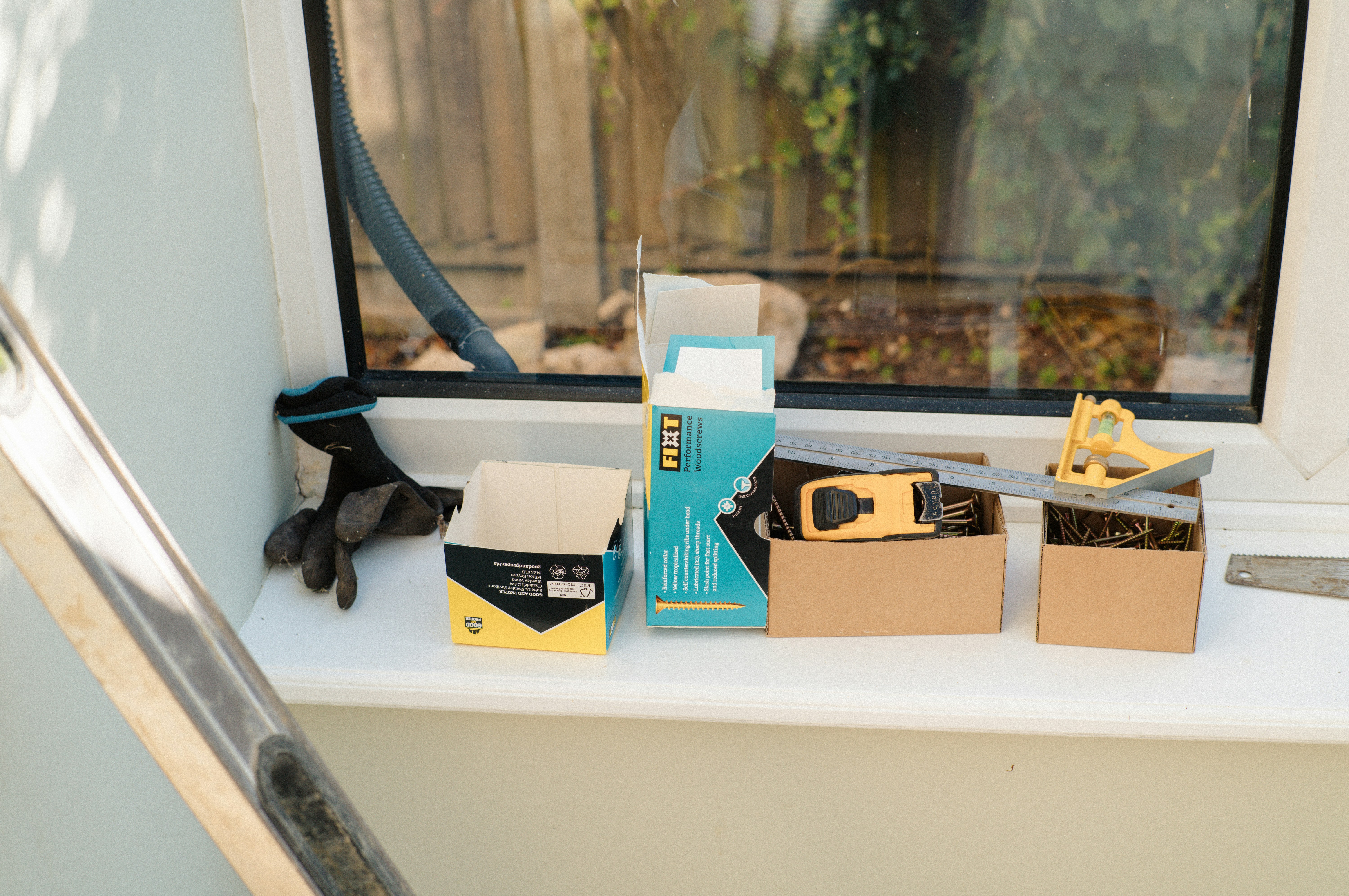 Sunlit windowsill with assorted cardboard boxes and packaging on display; a small workshop scene inside a bright room.