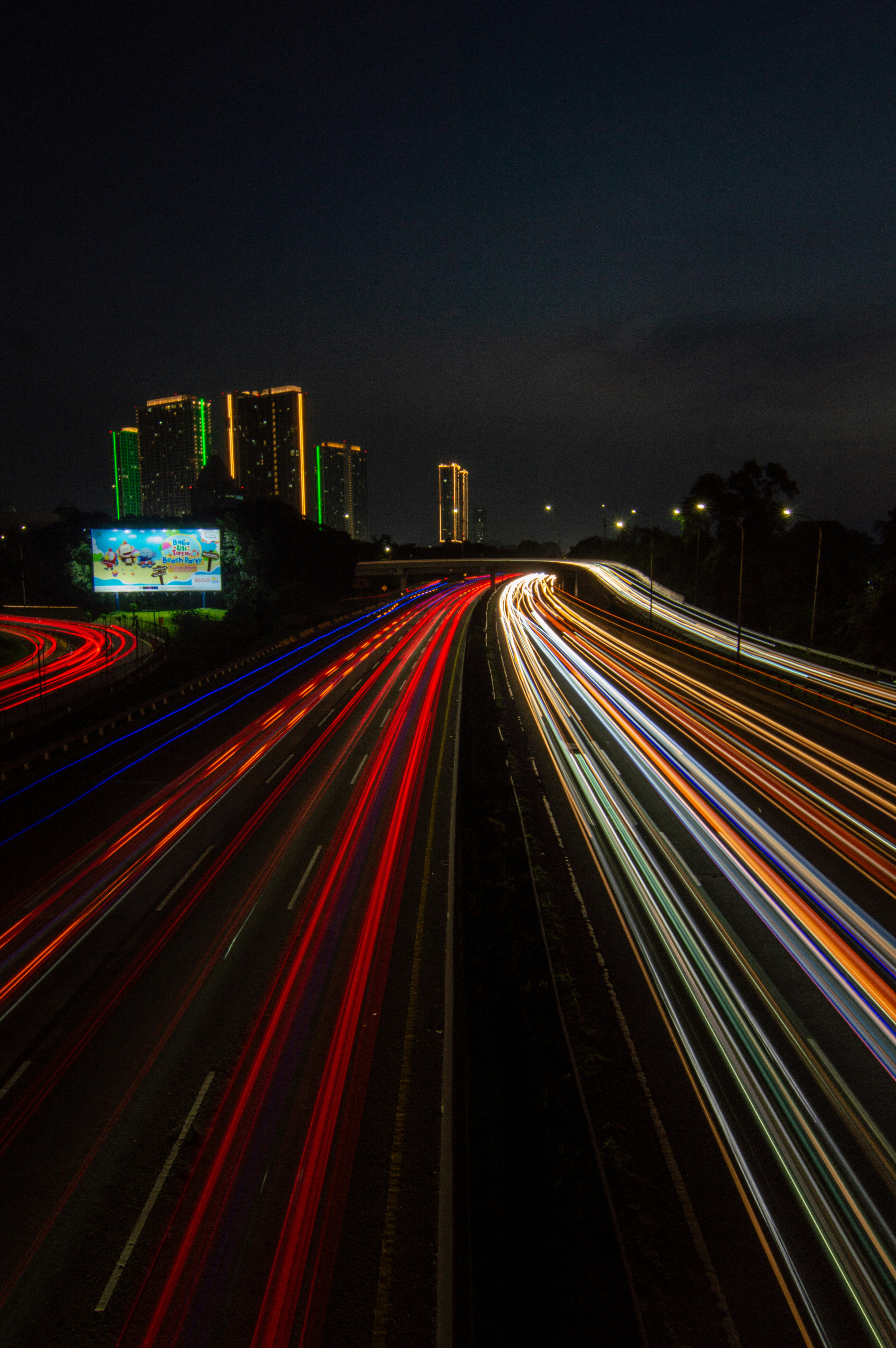 City Night Motorway: Light Trails Converge toward a Neon Skyline