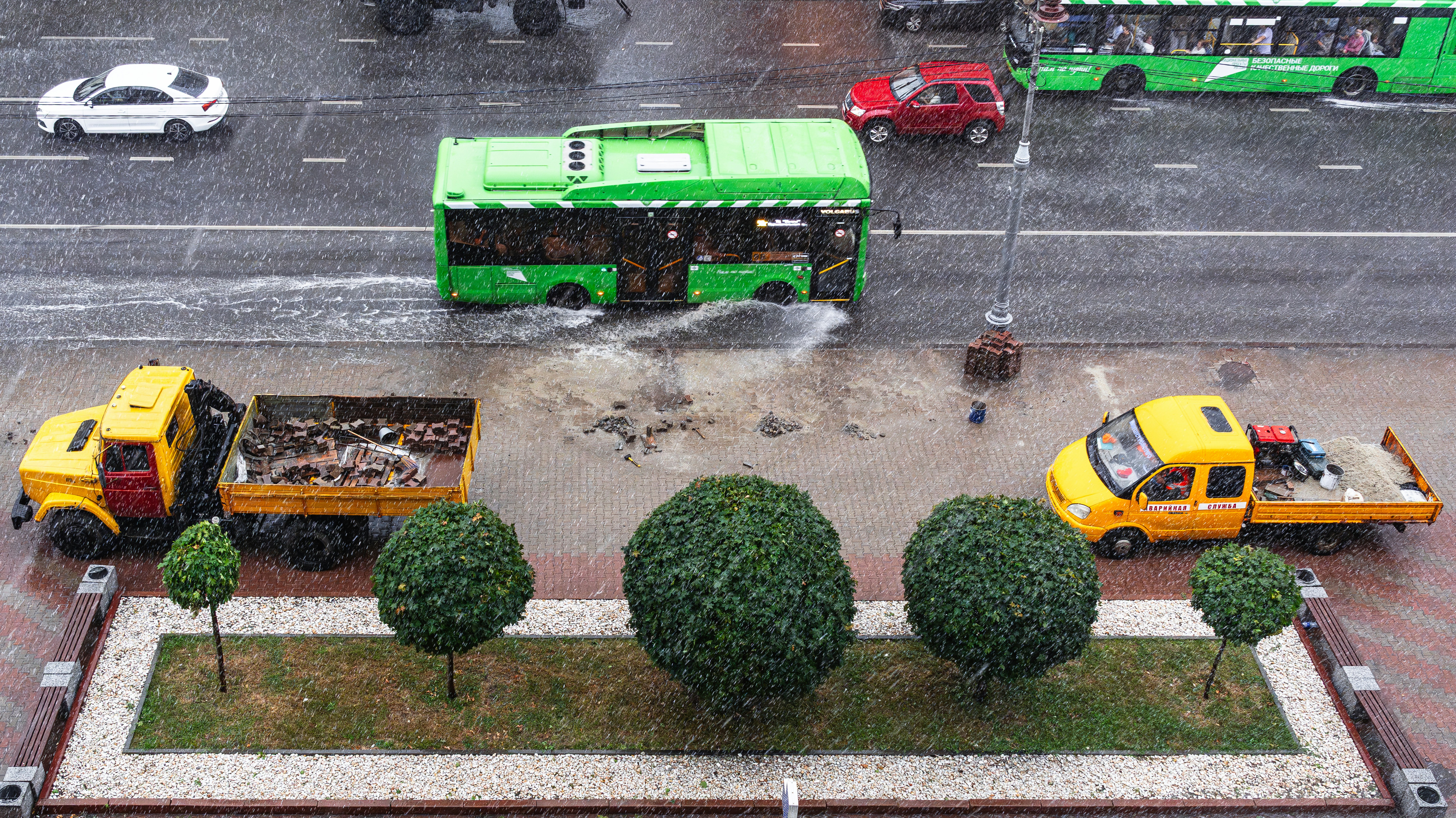 Urban Street in Rain: Aerial View of Buses, Cars, and a planted median
