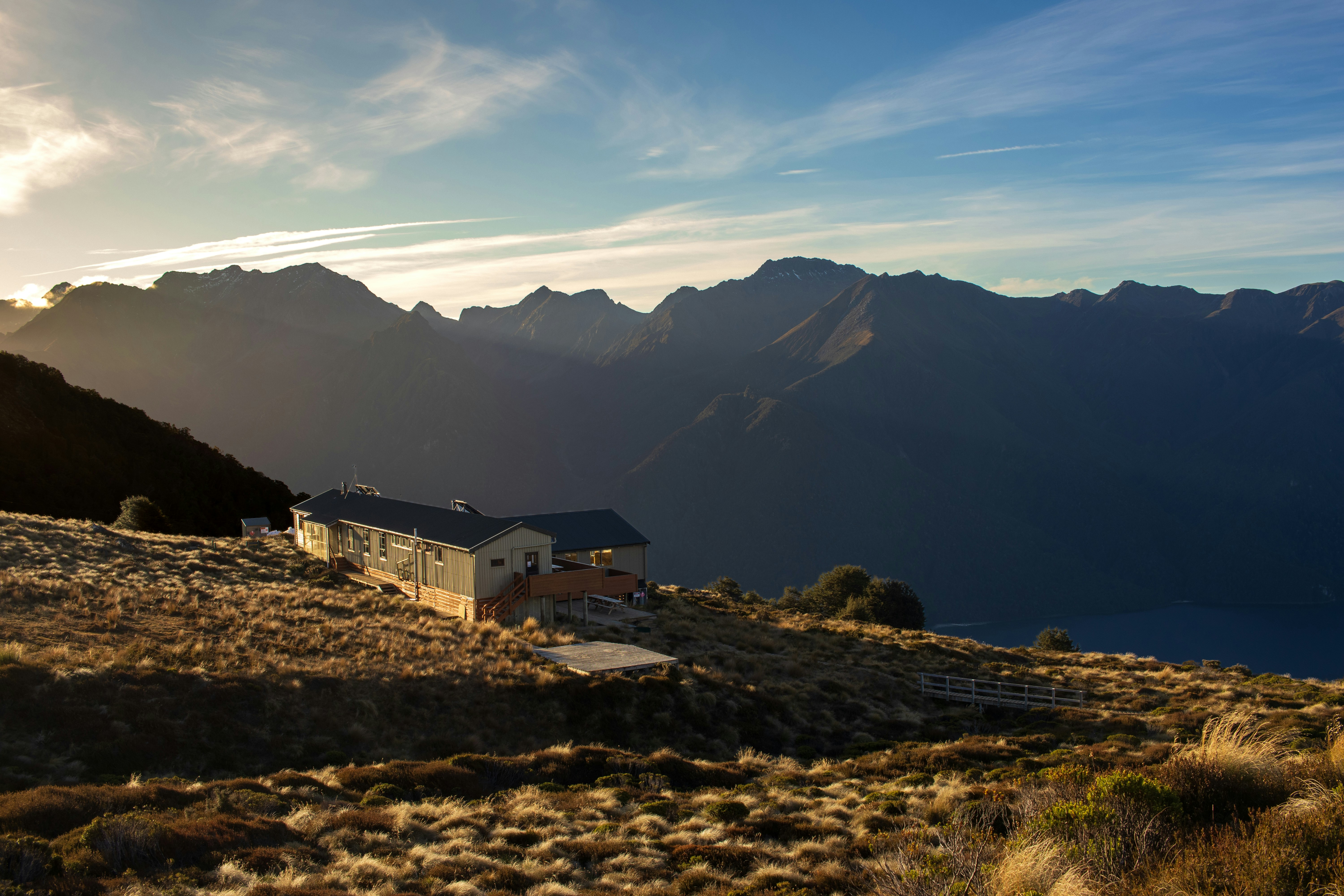 Sunlit hillside retreat beneath a jagged alpine horizon