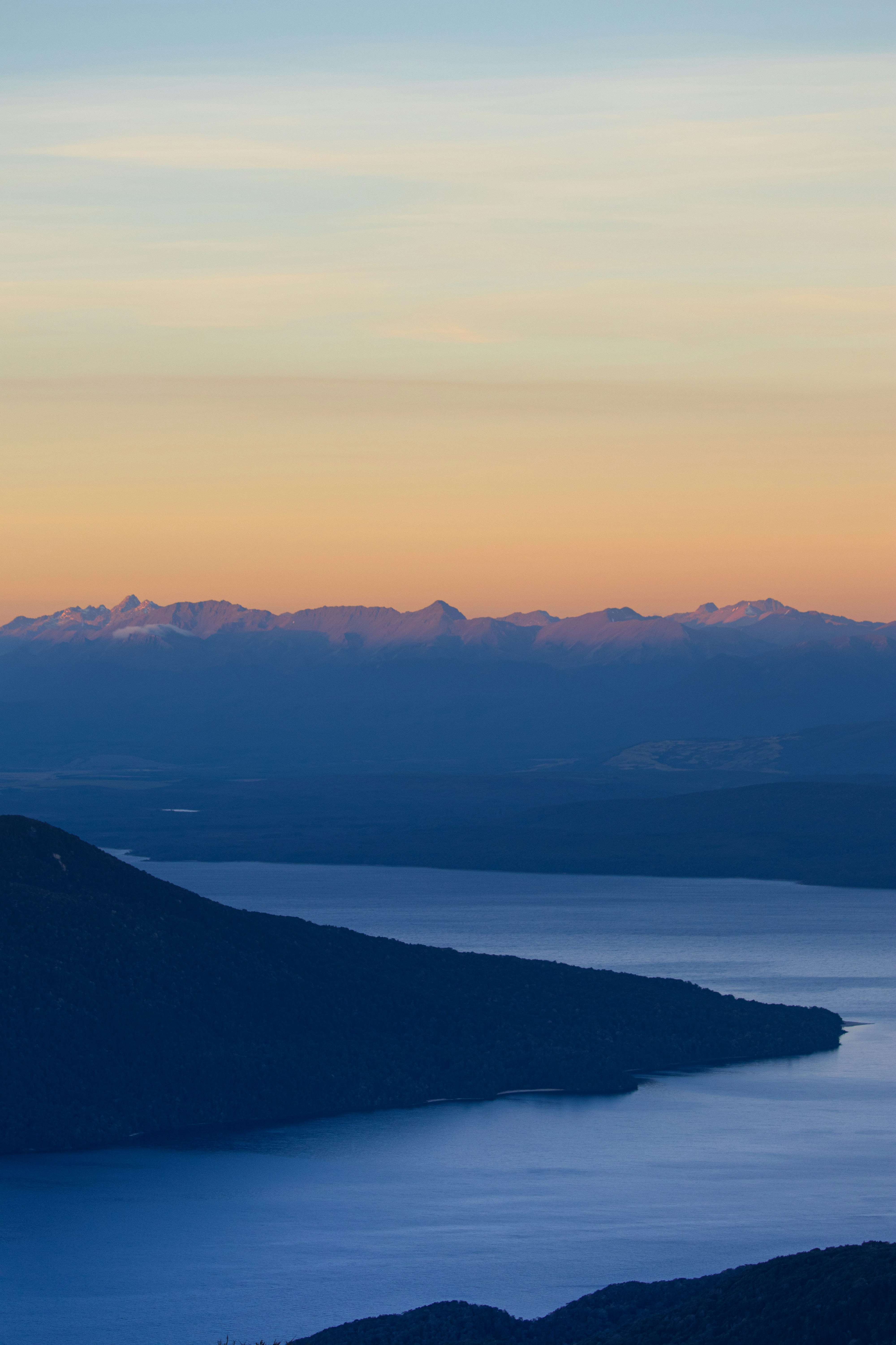 Distant Horizon: Snow-Capped Ridge Beyond a Serene Fjord at Dusk