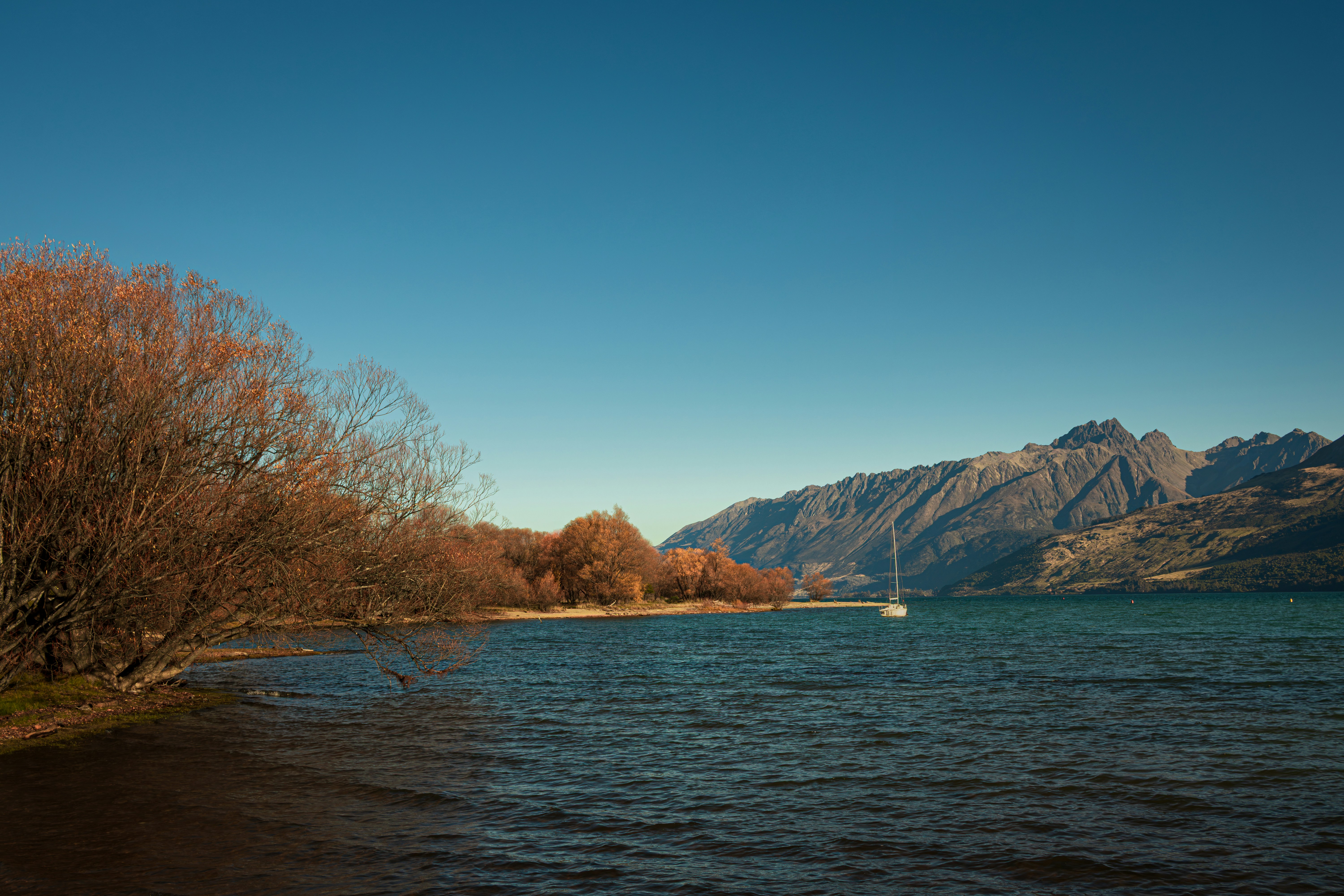 Lakeside Reverie: A Sailboat at the Foot of Quiet Mountains