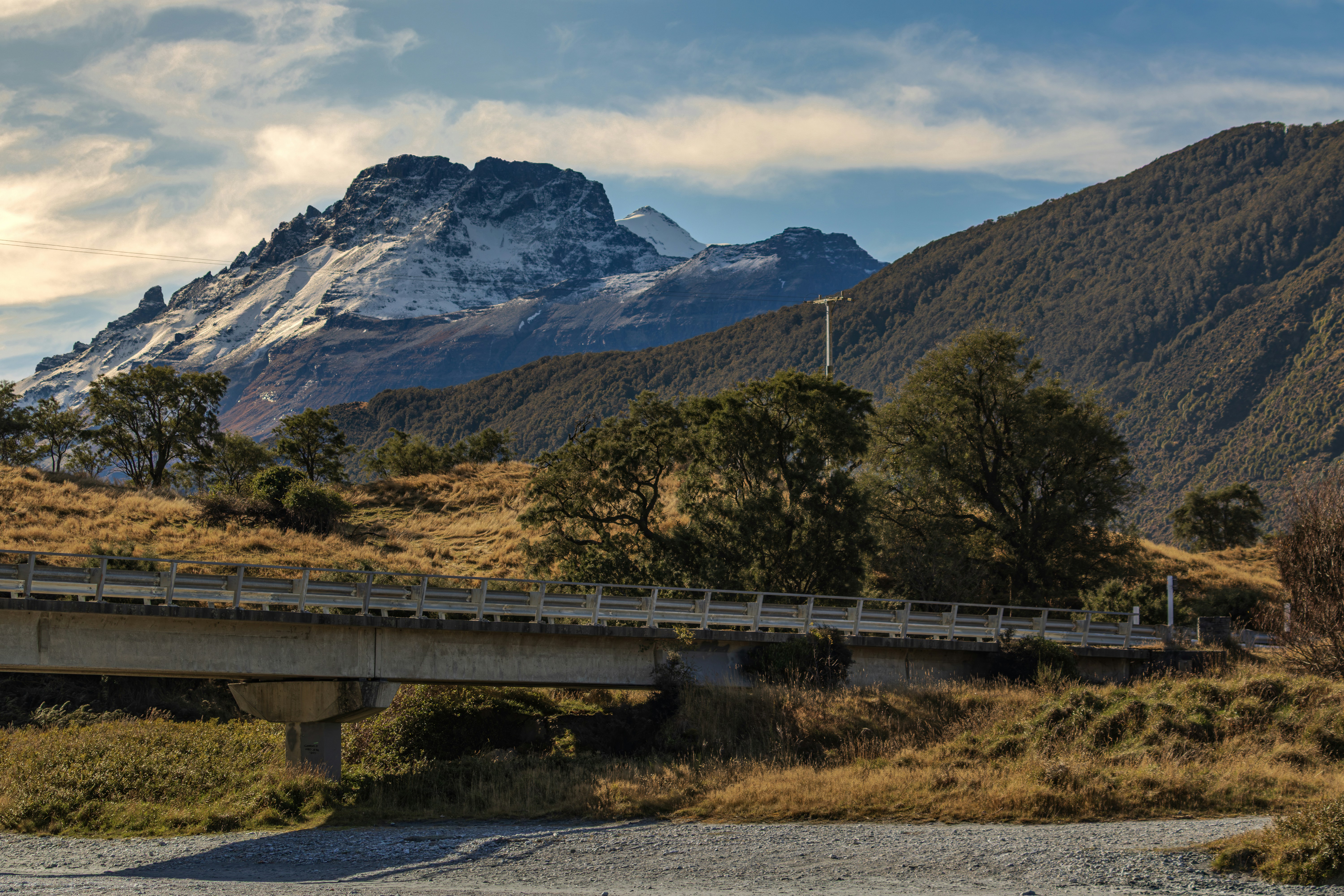 Bridge Over Golden Foothills Beneath Snow-Dusted Peaks