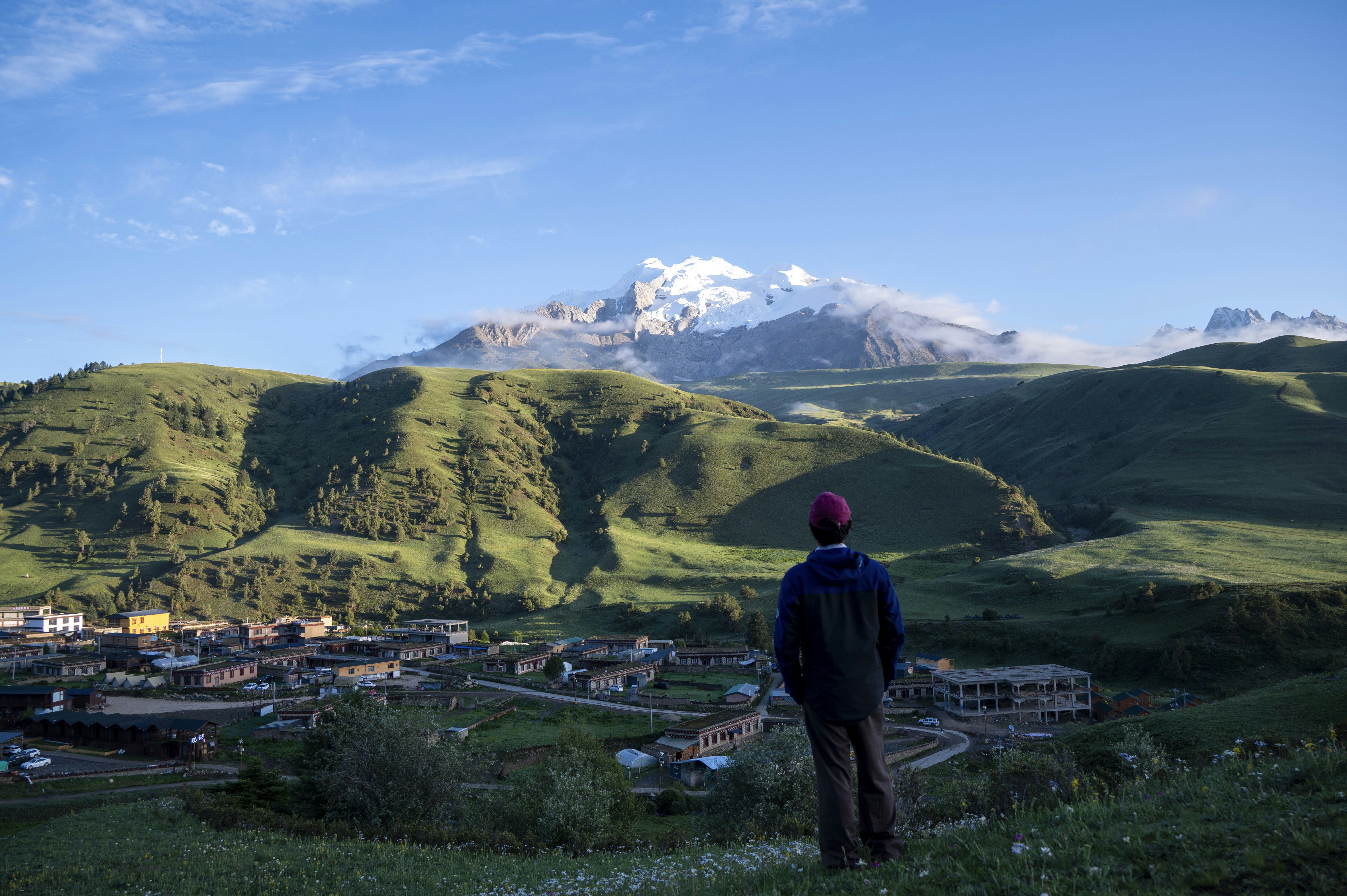  lone observer on a emerald hillside overlooking a valley town