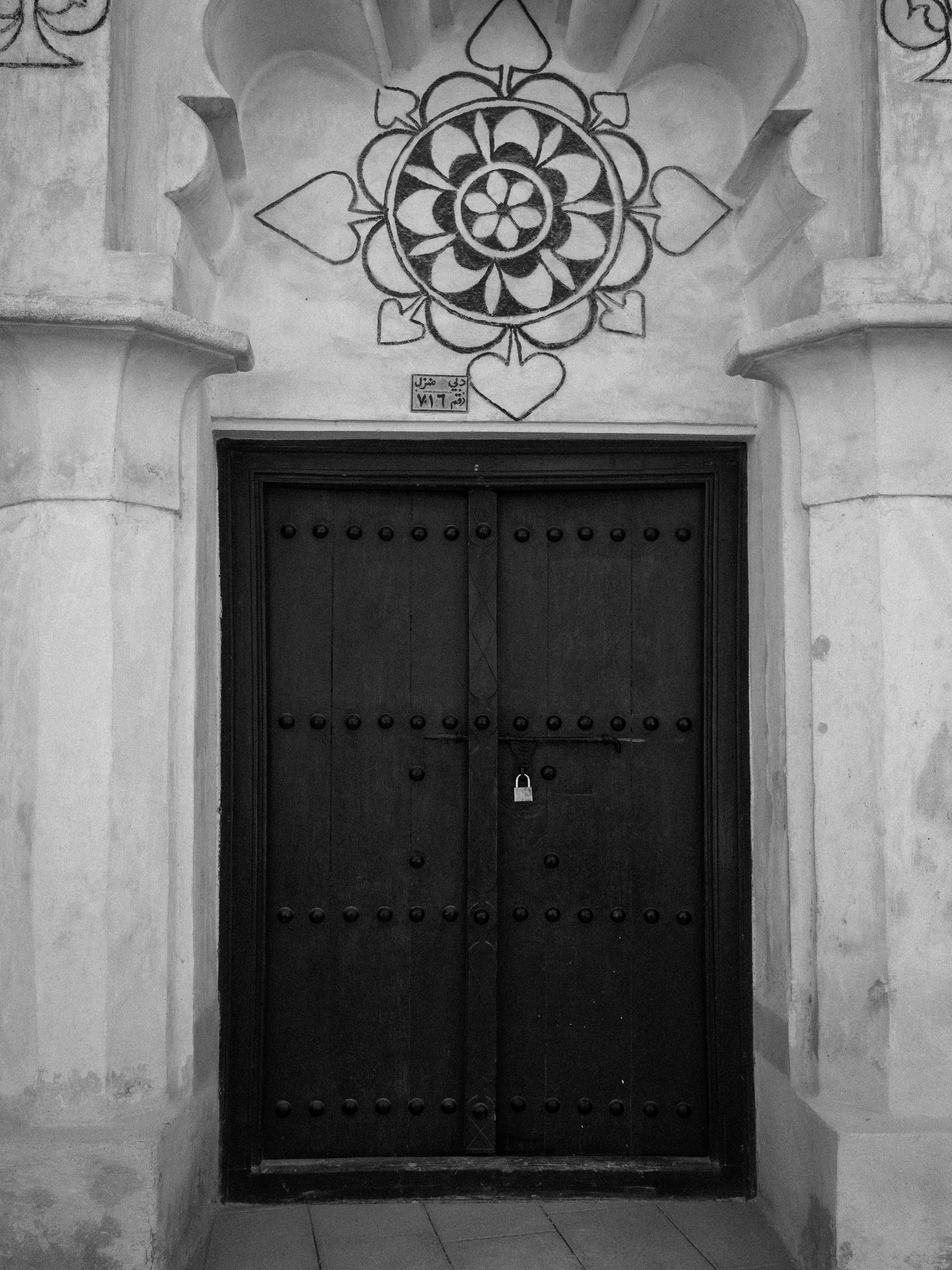 A black and white photograph of an ornate traditional wooden door with architectural details.