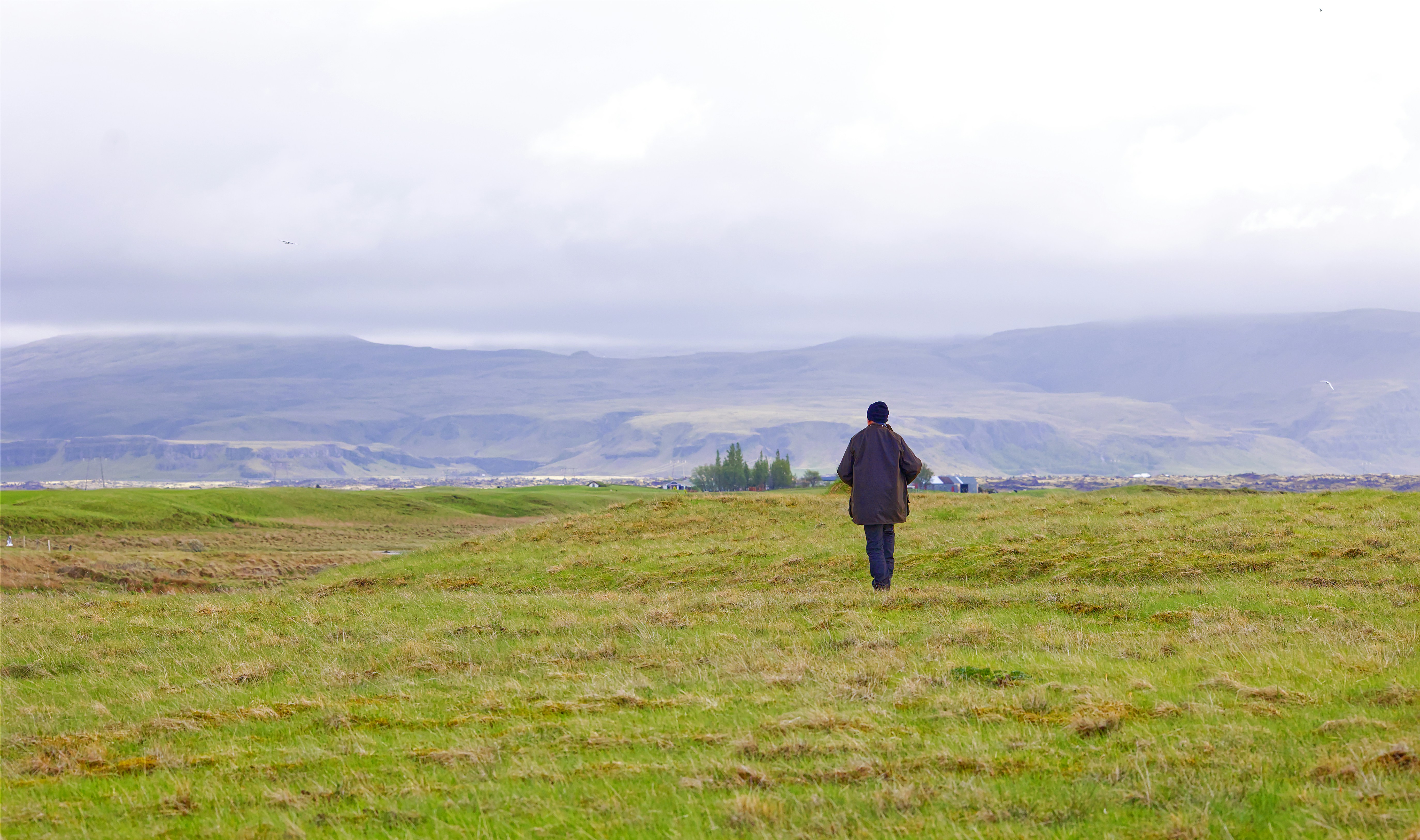 Lonely Walker Across Rolling Moor Under Expansive Sky