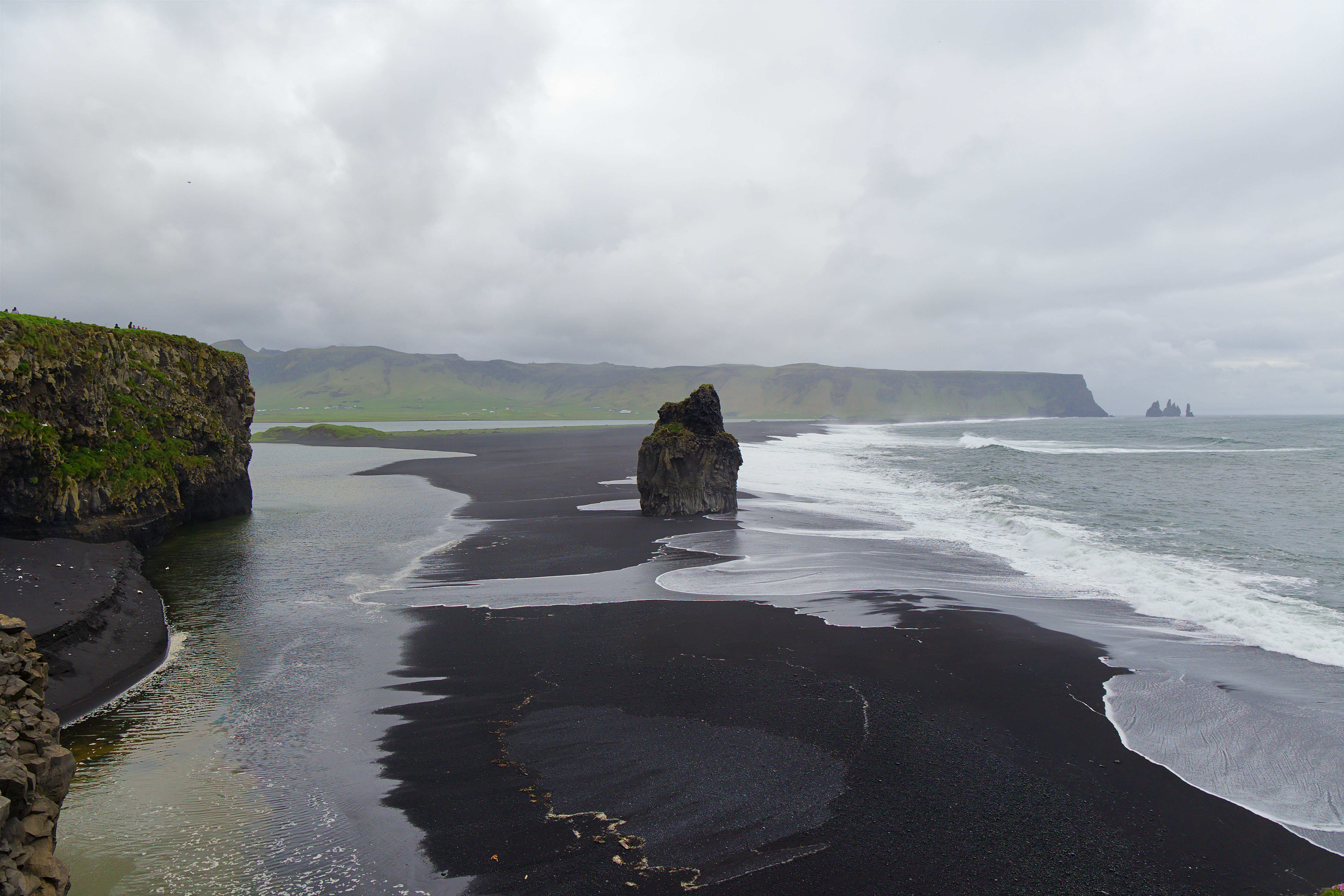 Black Sand Coastline under Cloudy Skies with Sea Stack Promenade