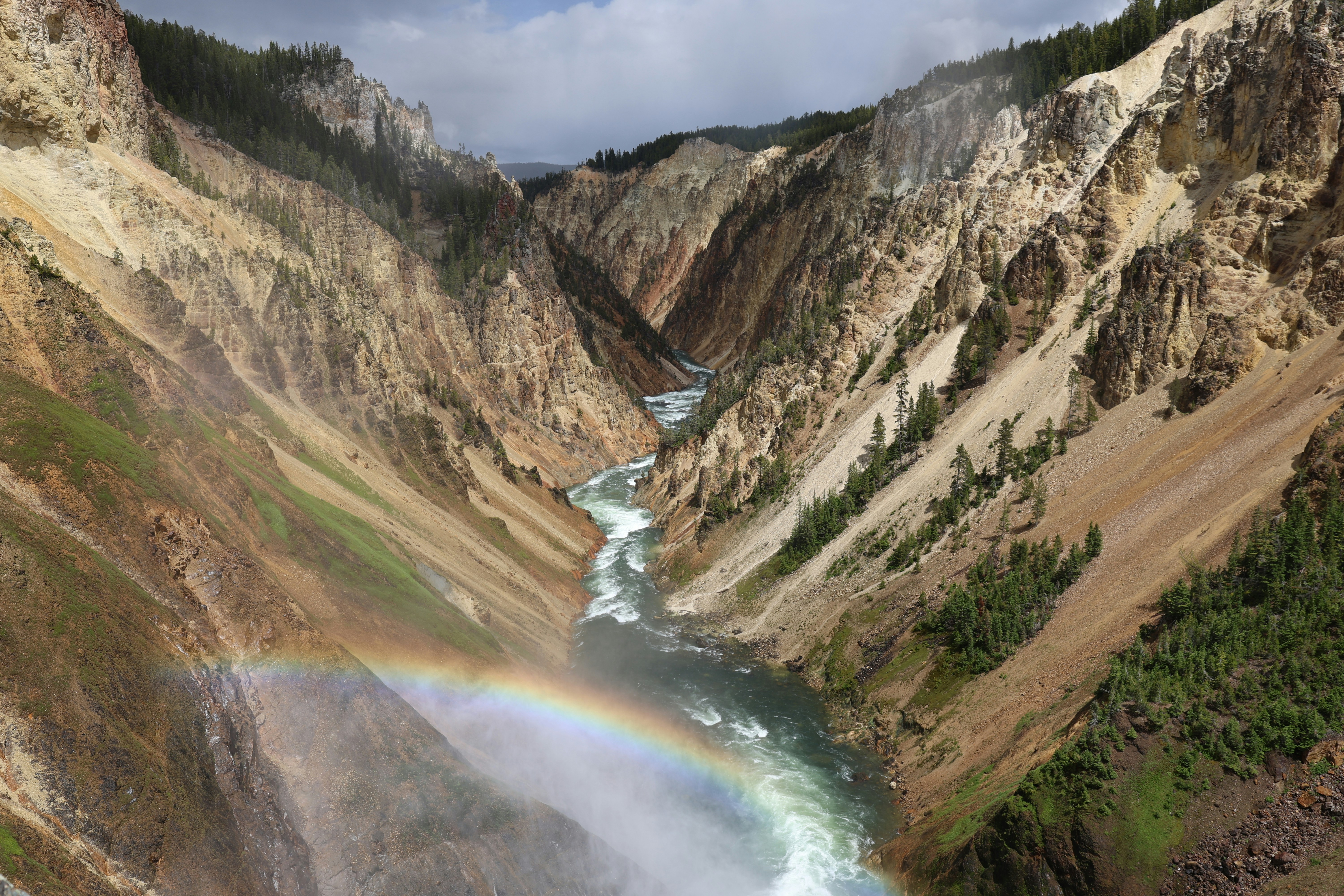 Rainbow over a winding canyon: river slicing through colorful cliffs
