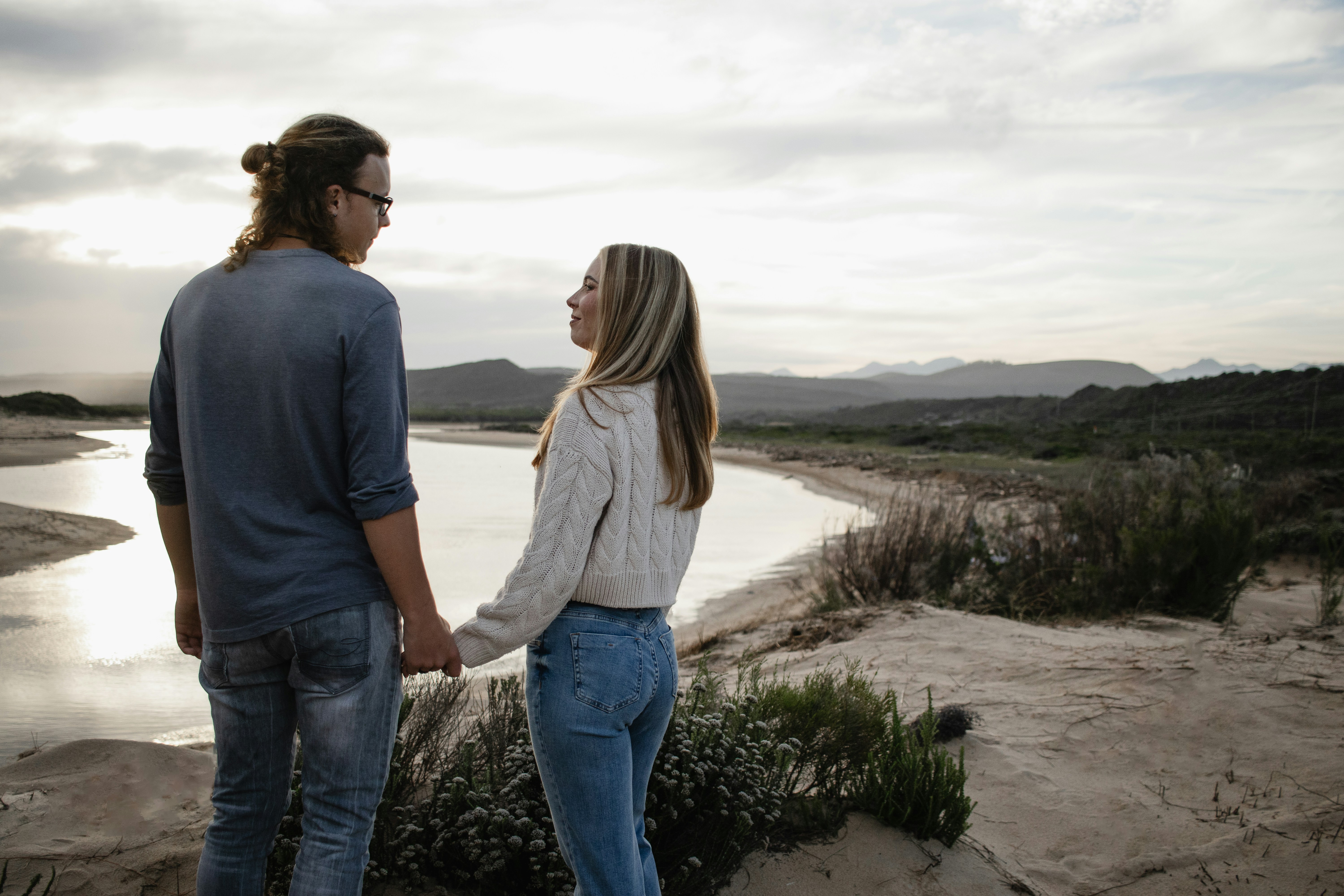 Holding Hands at Sunset Over Quiet Shoreline