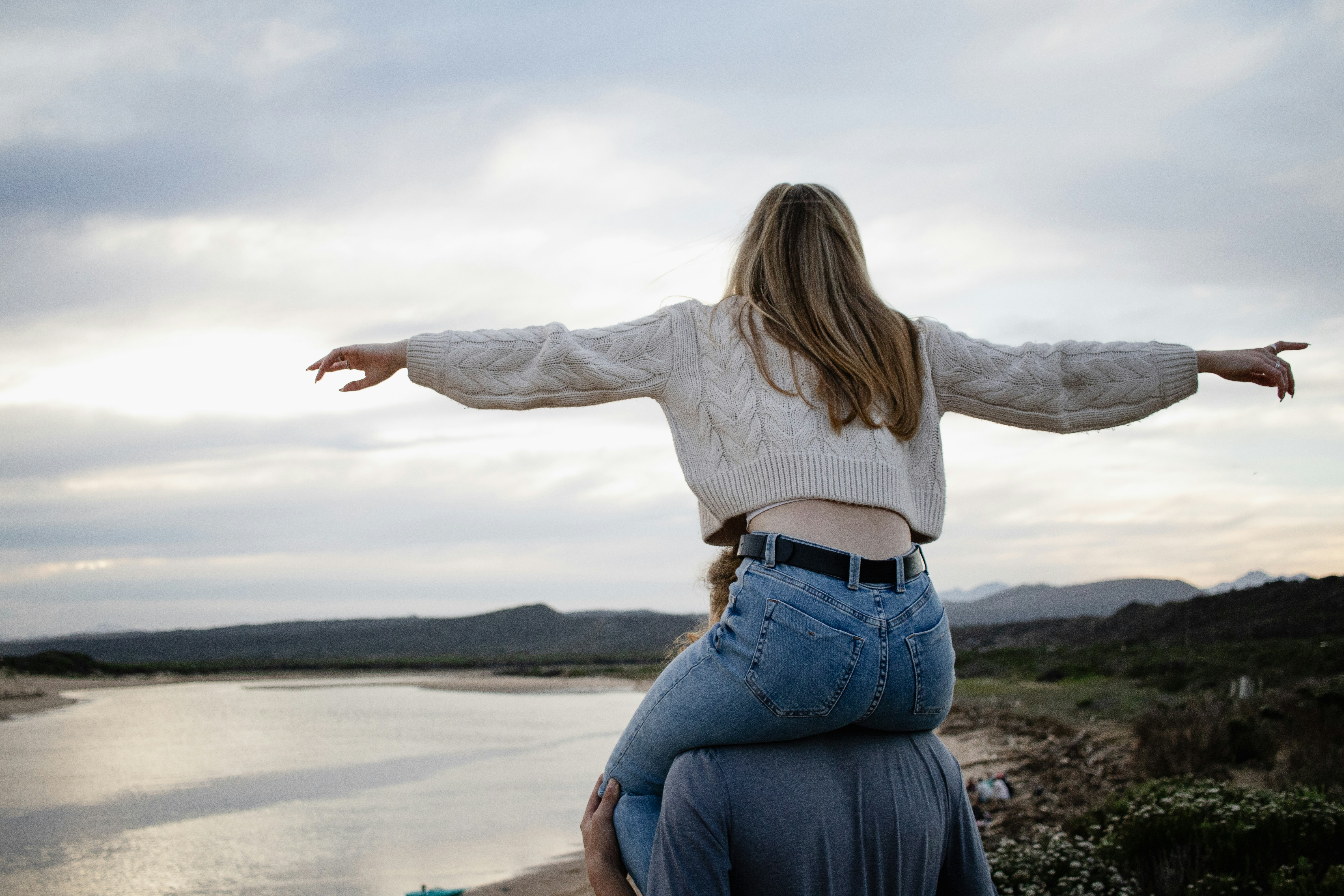 Elevated Freedom: Woman With Arms Outstretched Over a Quiet River