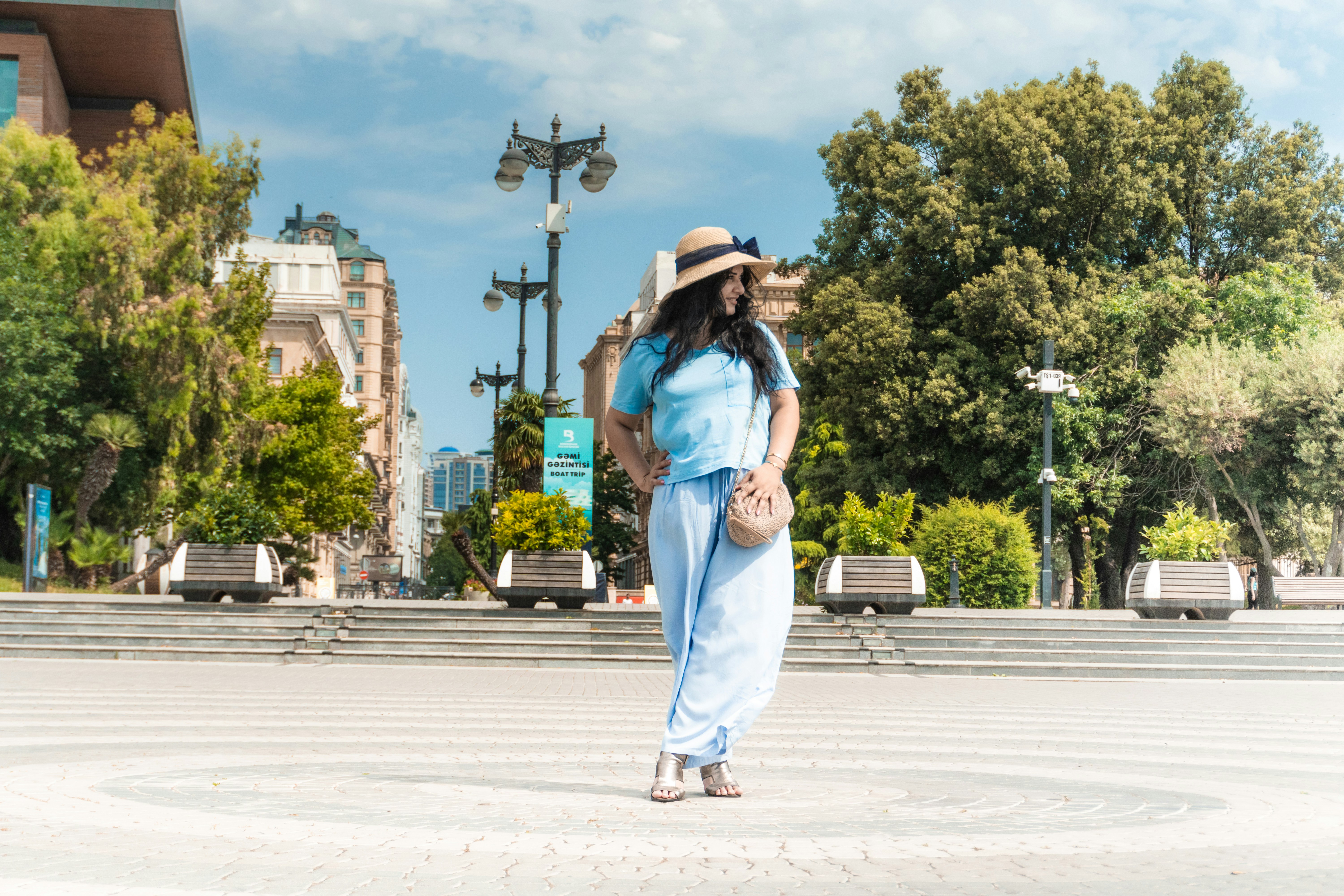 City stroll in pastel blue: a woman in a flowy dress under summer light
