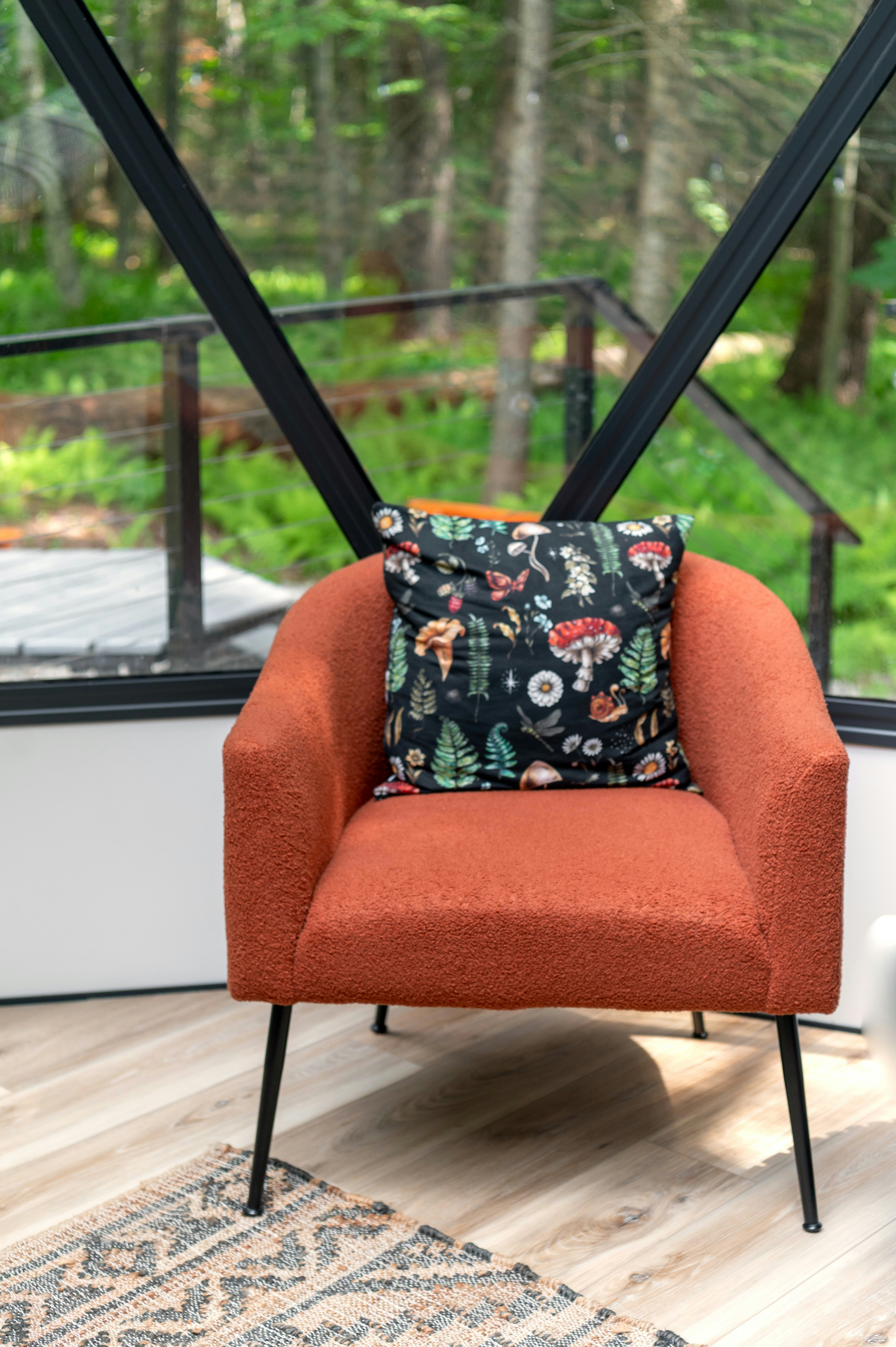 Portrait of a Cozy Accent: An Orange Armchair with Floral Pillow in Glass-walled Space