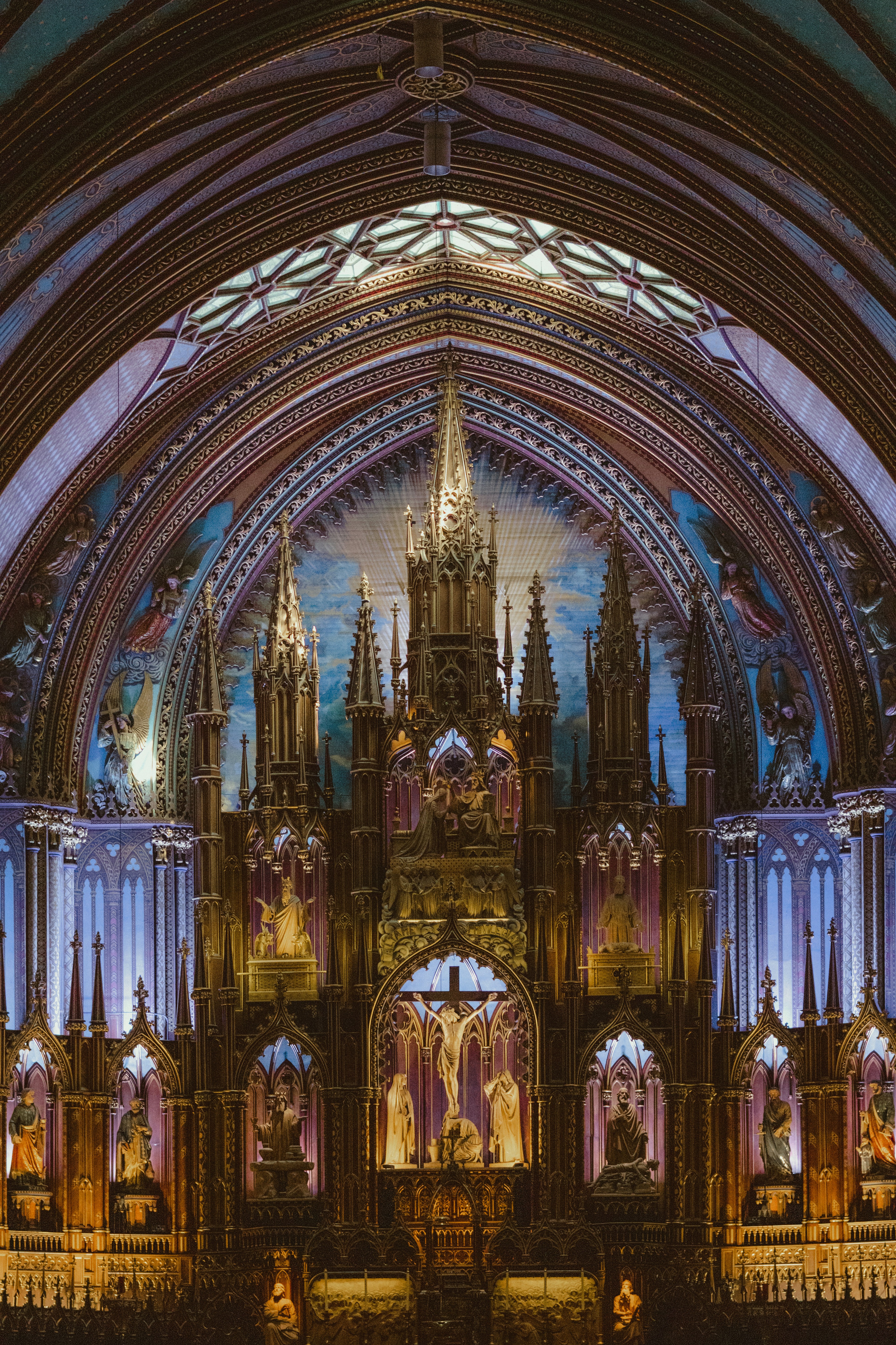 Richly lit Gothic cathedral interior with towering spires and ornate altarpiece, emphasizing the central altar and vaulted ceiling.
