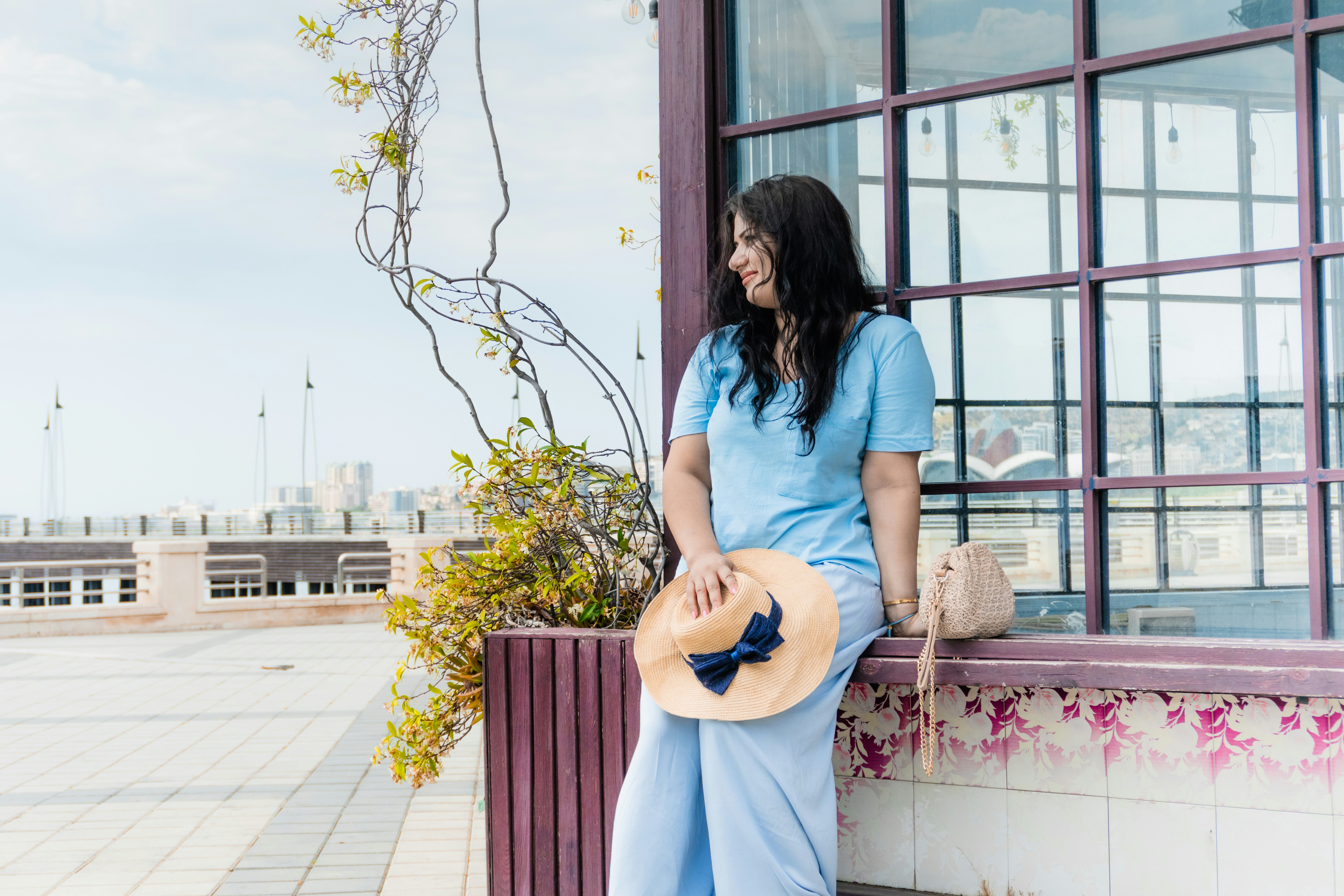 Blue dress, sunlit veranda: a quiet portrait by the glass wall