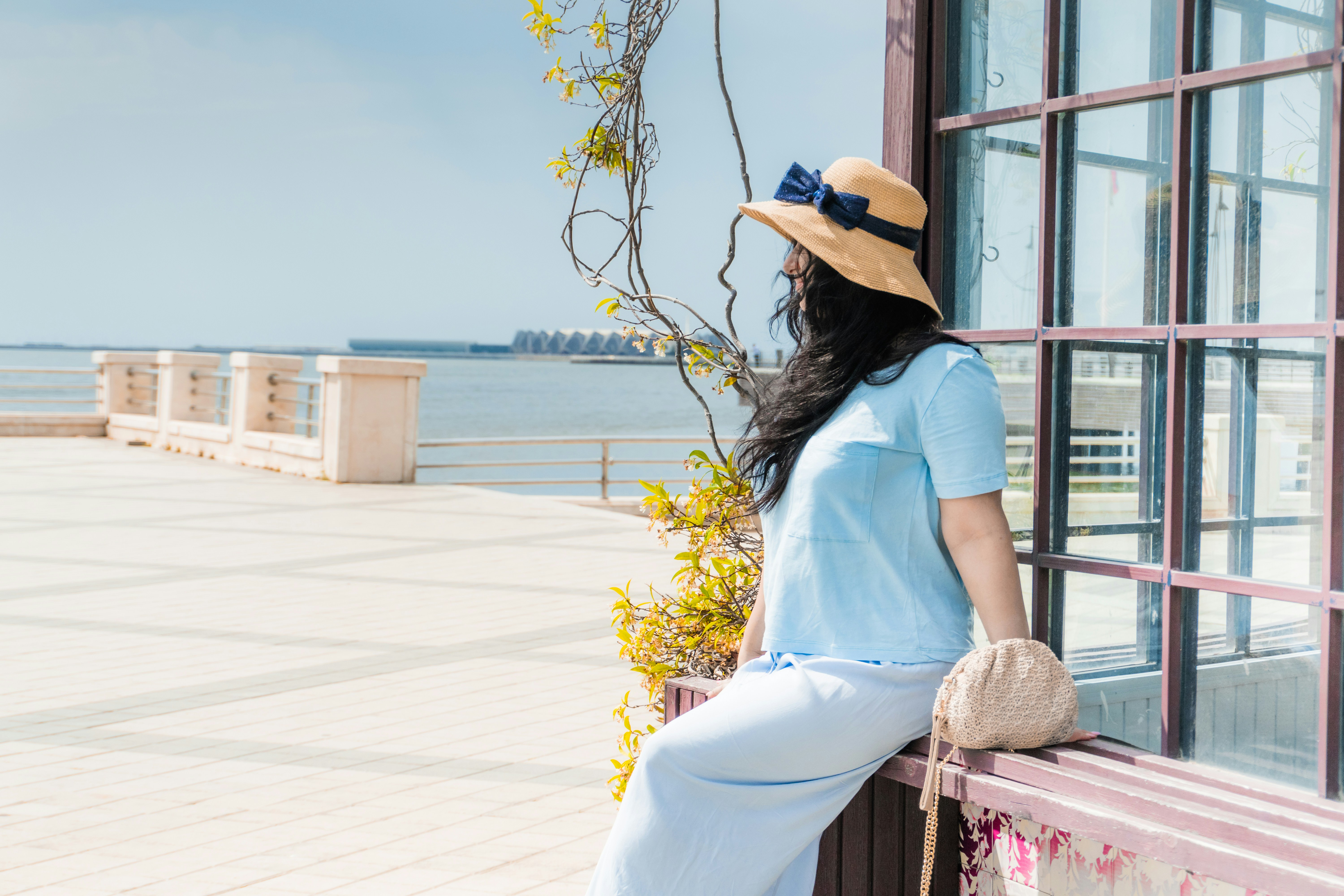 Sunlit Seascape Picnic: A Woman in Light Blue by the Windowed Terrace