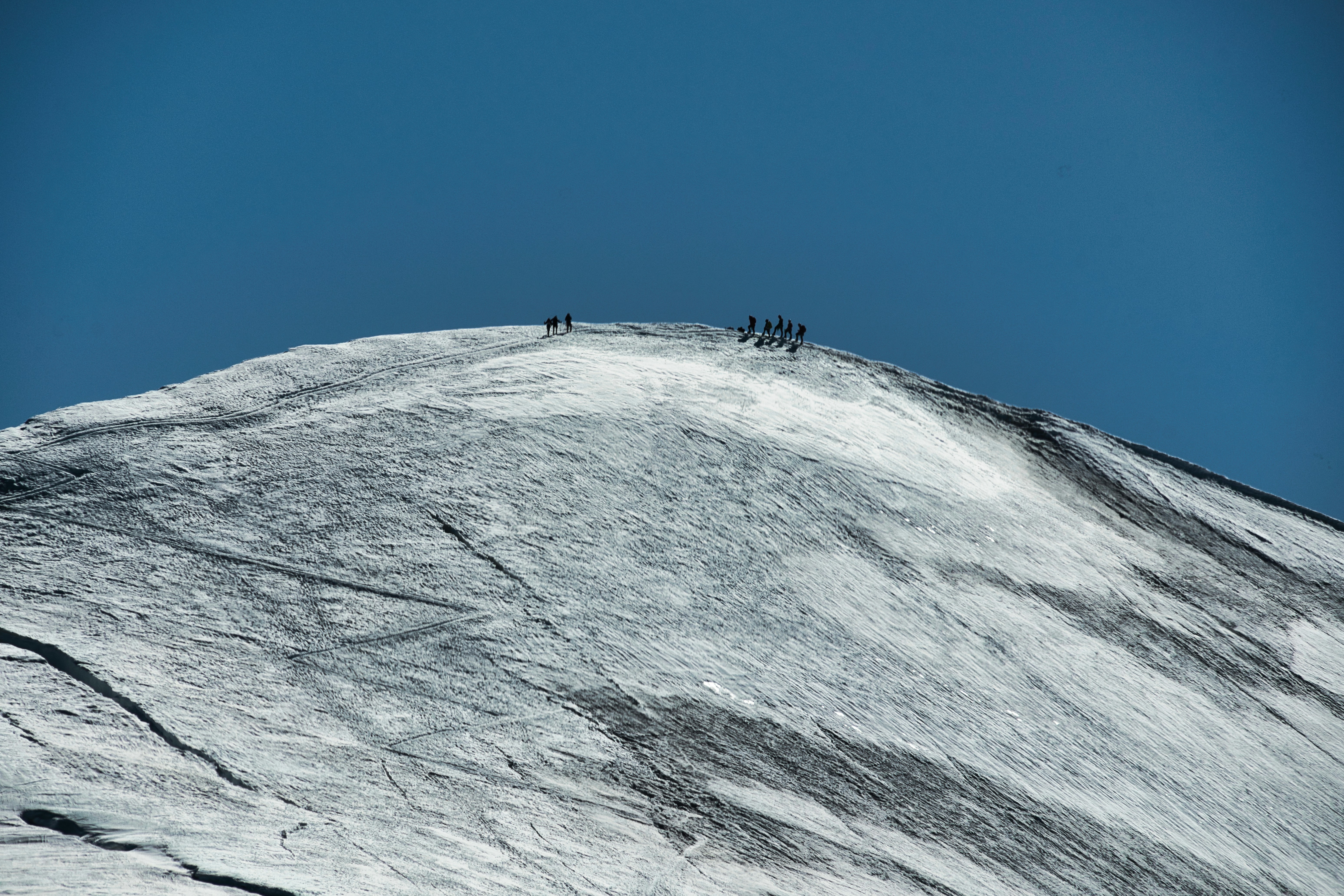 Crowd at the Crest: A Snowy Summit Under a Clear Blue Sky