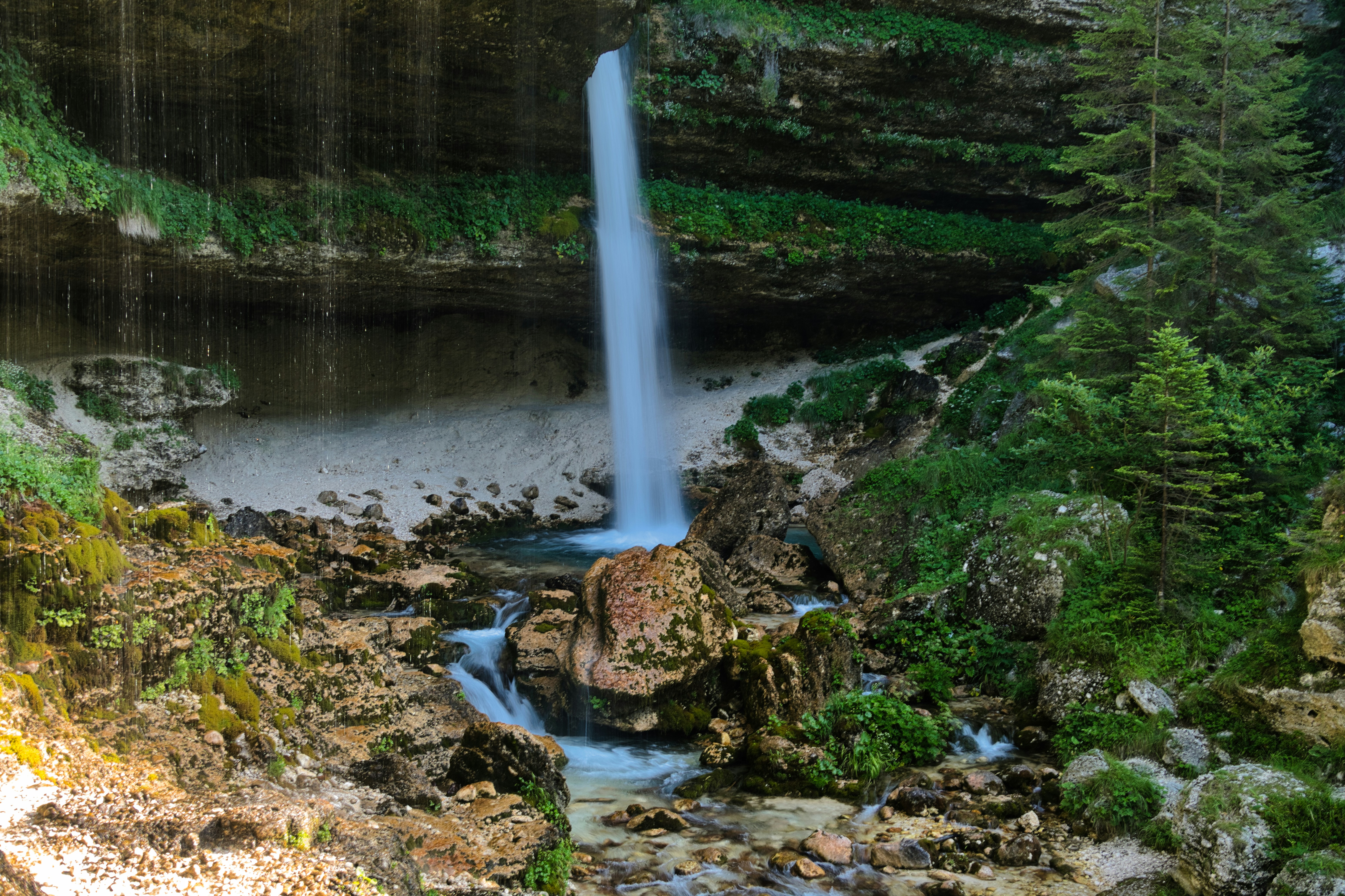 Cascading Silence: A Lone Waterfall Between Green Cliffs