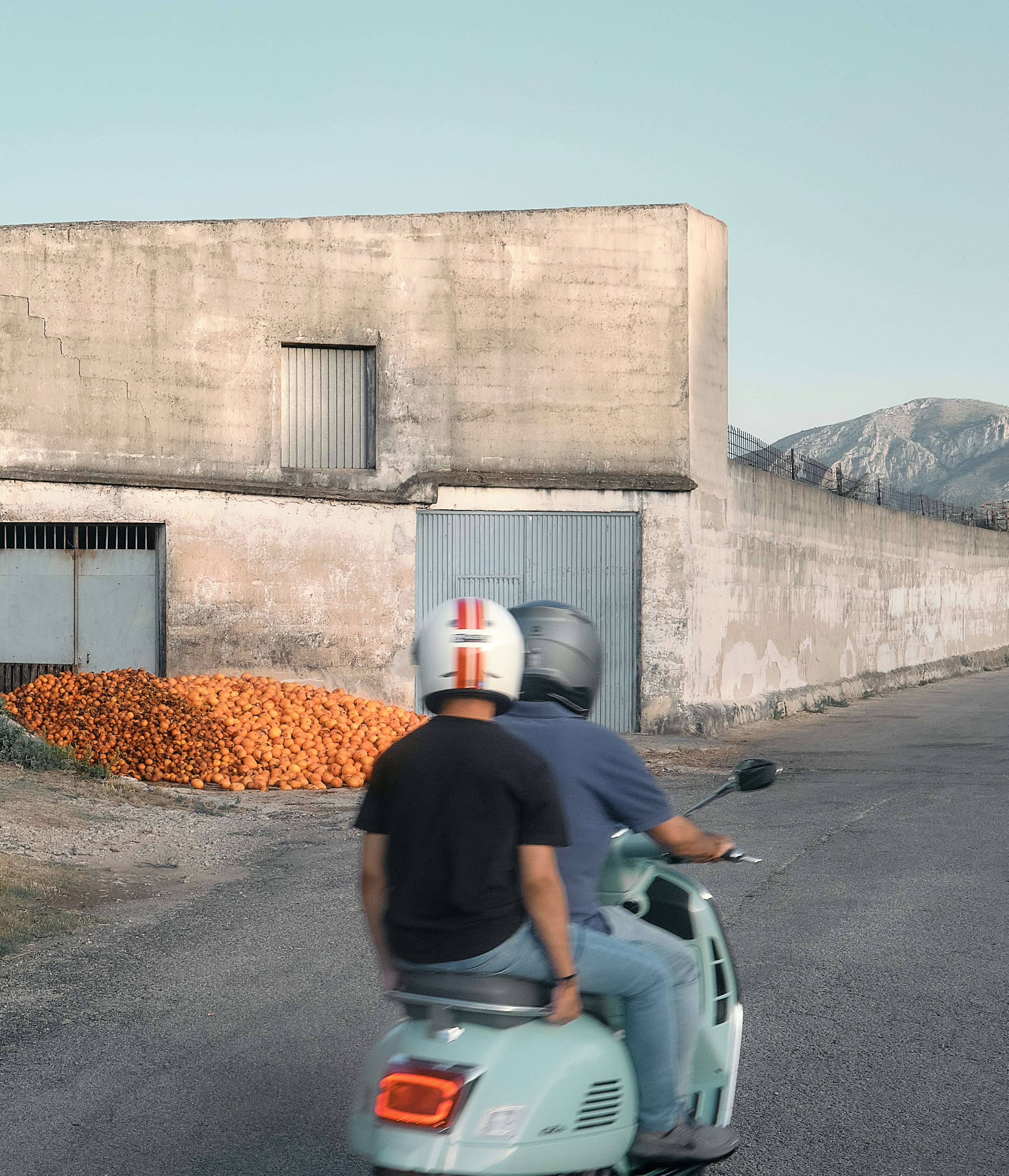 Scooter Duo Passing a Weathered Industrial Wake