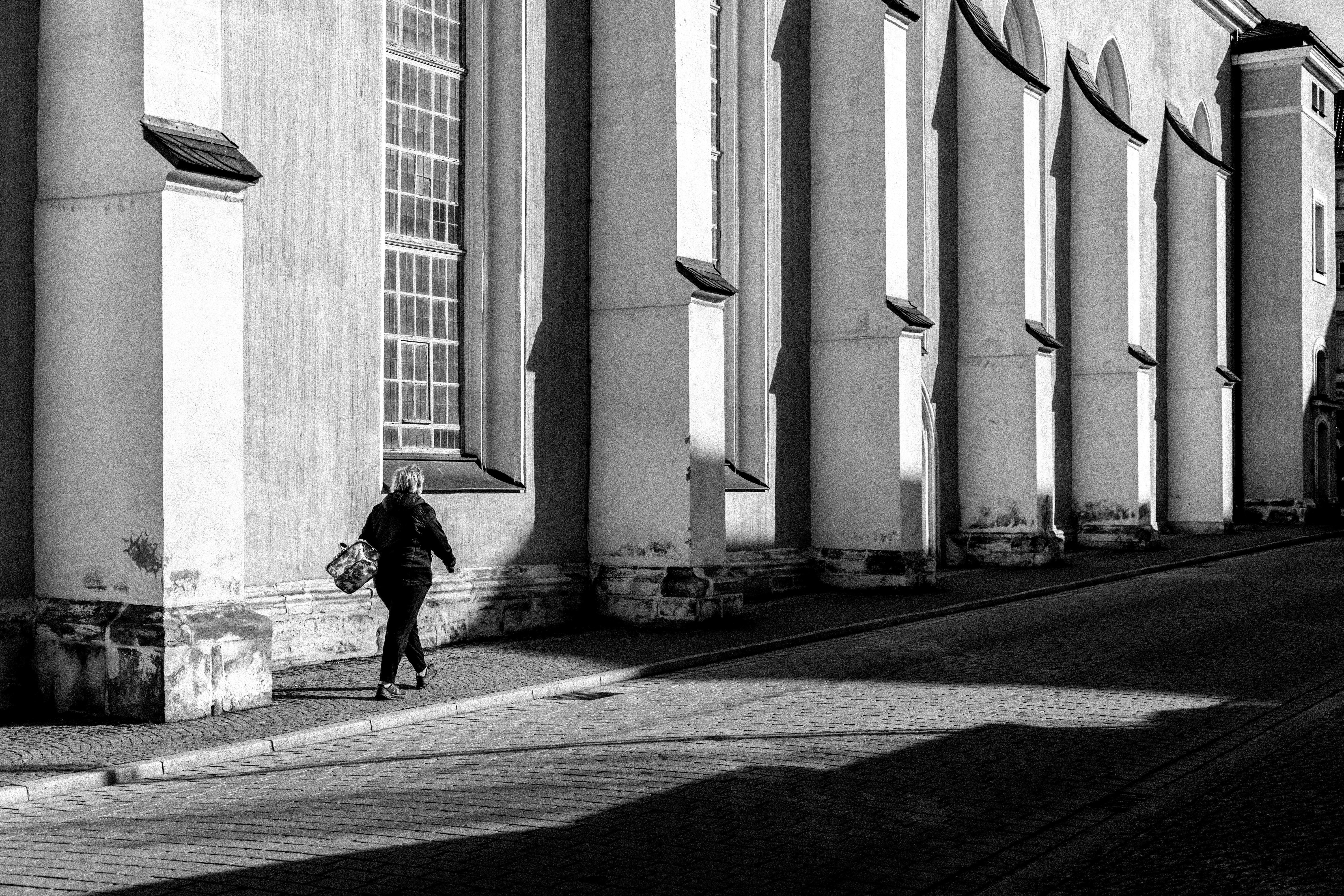 Lonely Pedestrian Along a Monolithic Facade
