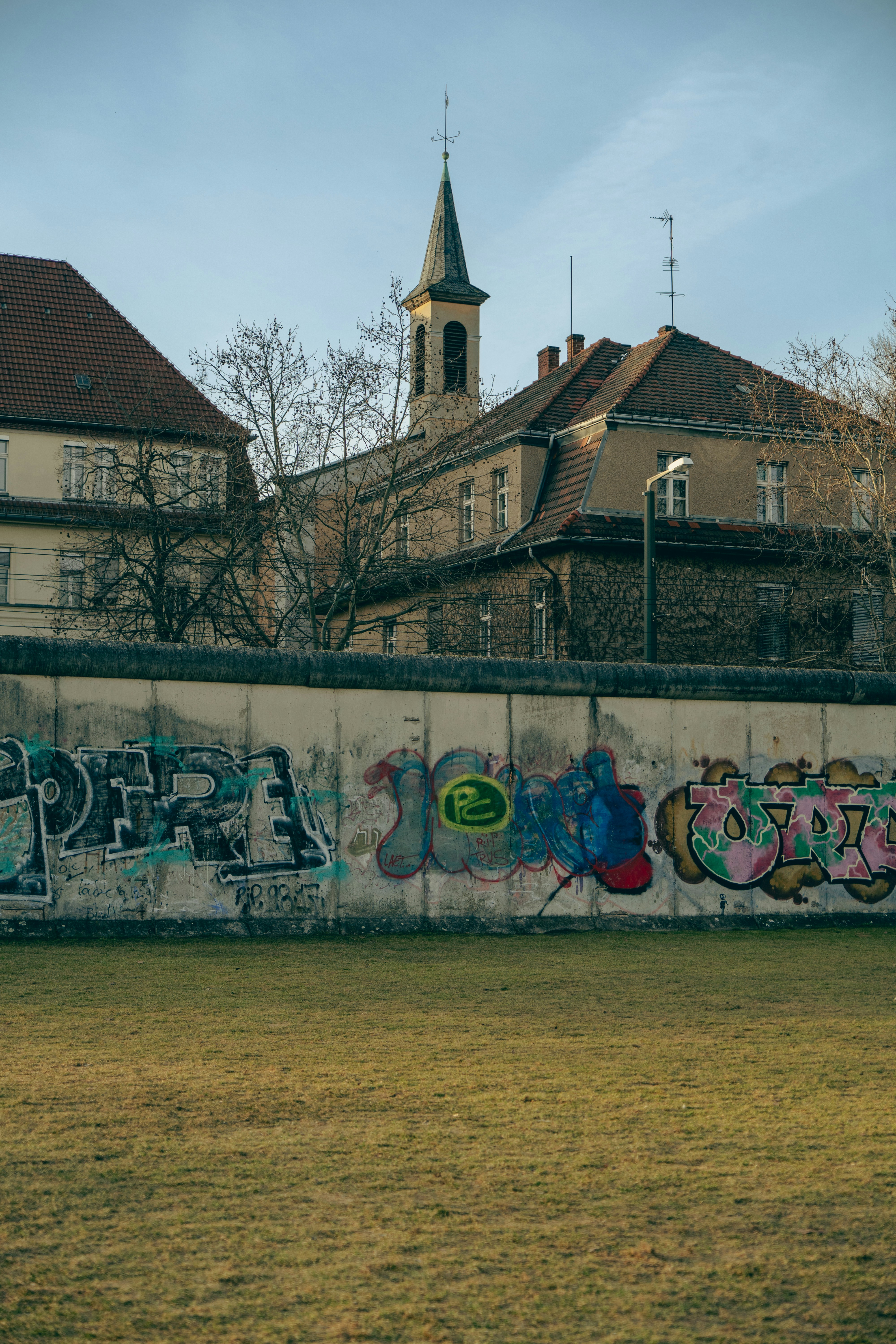 Graffiti Border Overlook: Urban Wall and Rooftops Above a Quiet Field