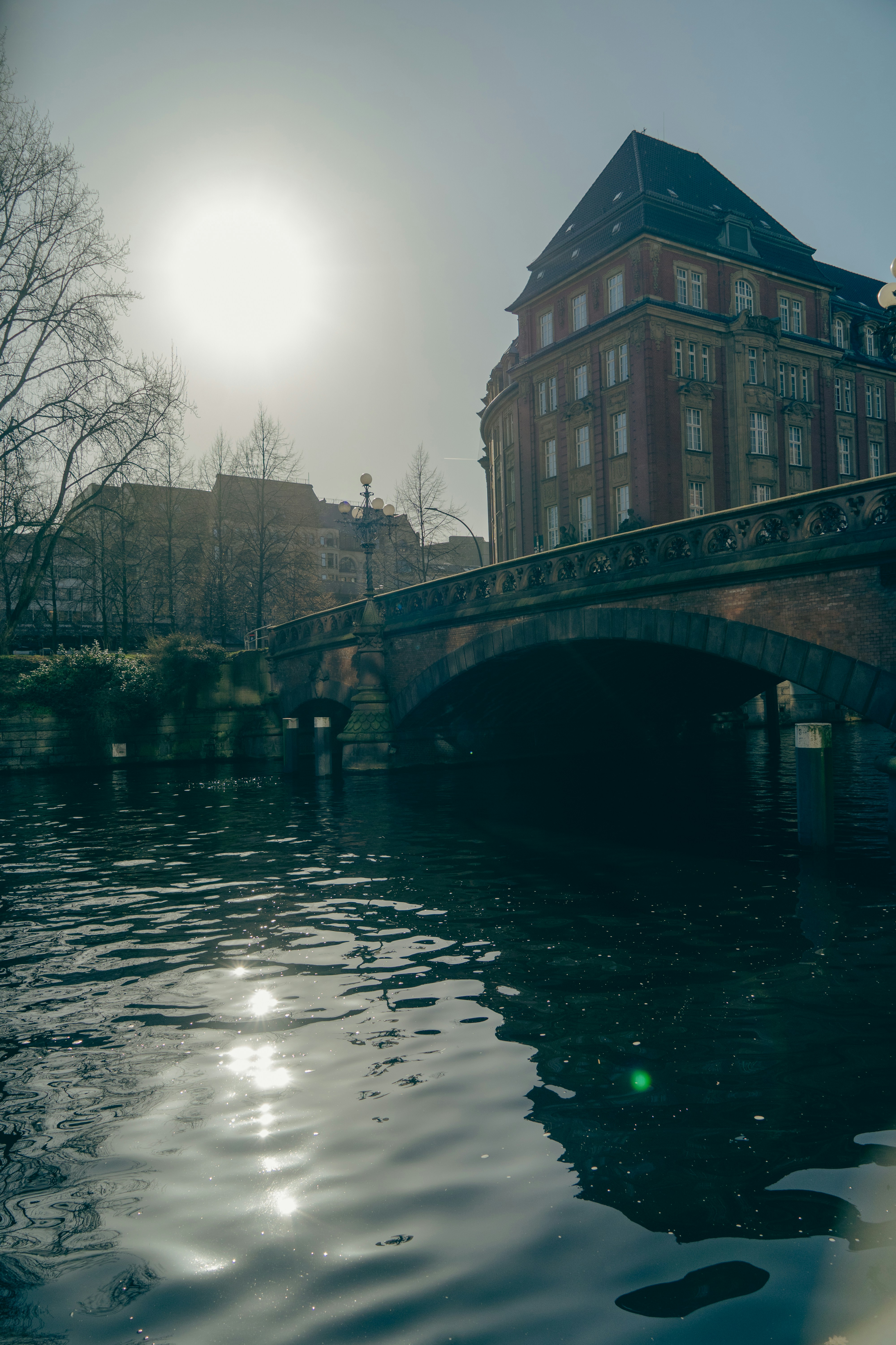 Sunlit Bridge and Historic Building Over Calm Waters