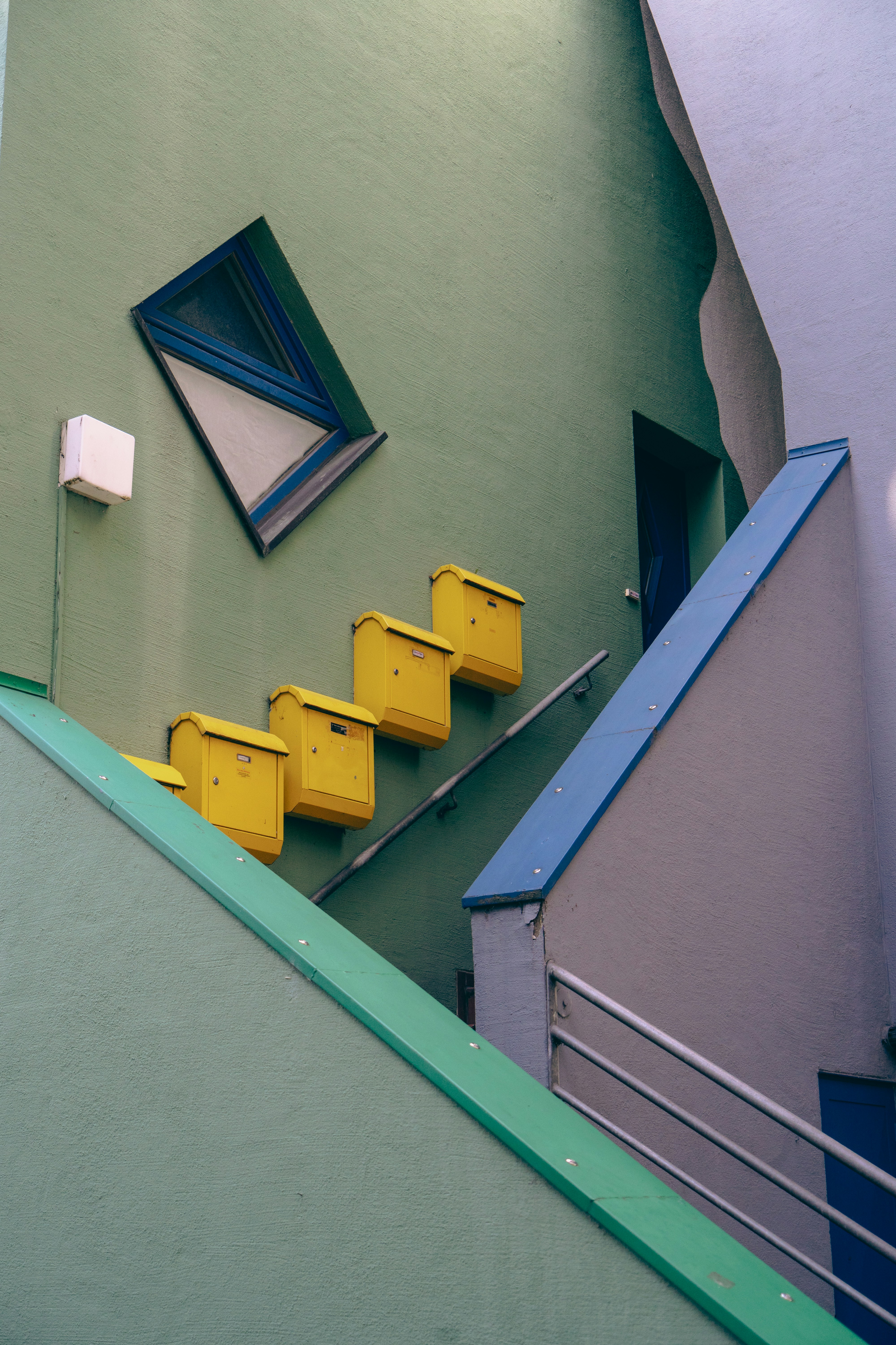 Colorful Staircase Cadence: Yellow Mailboxes on a Geometric Wall