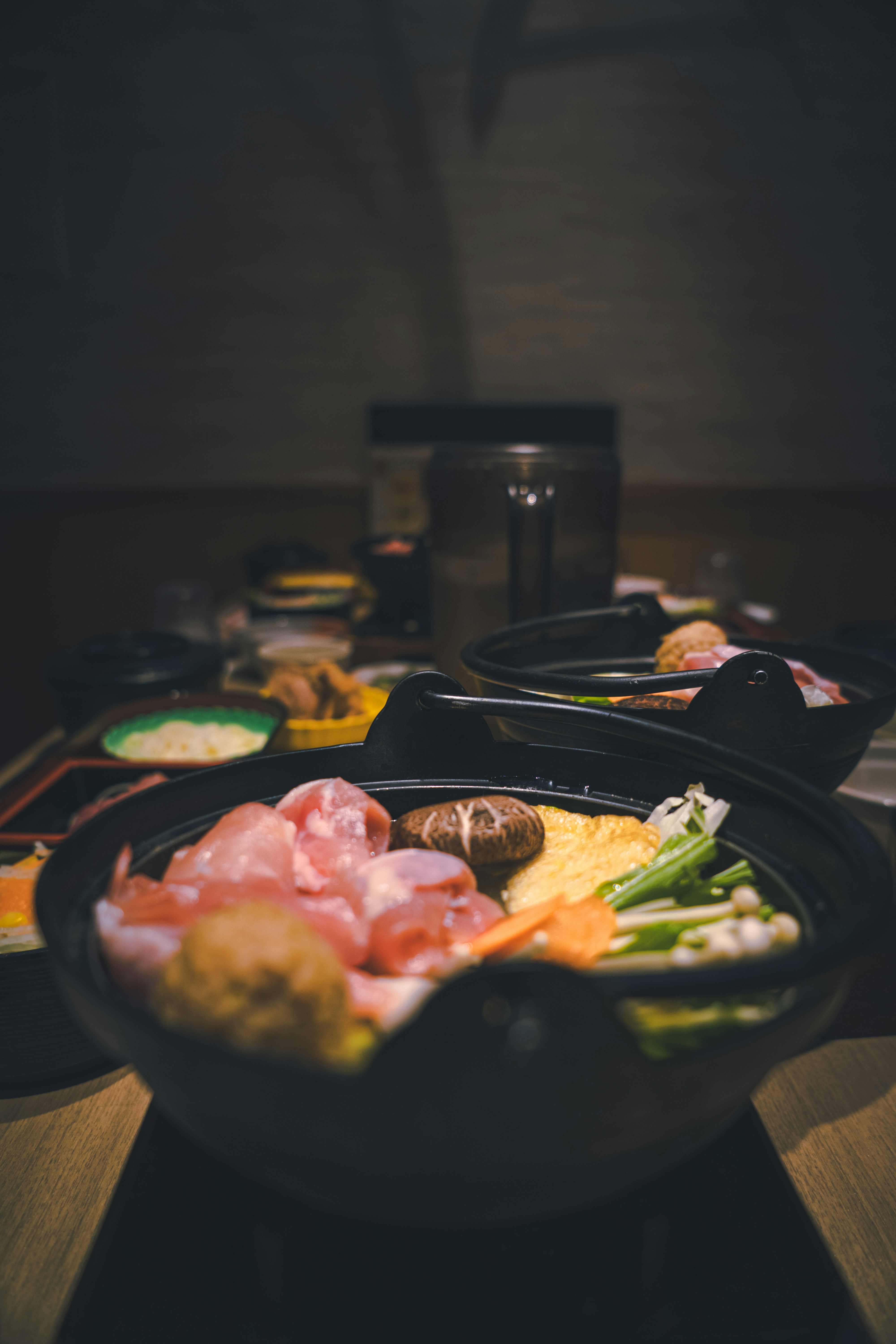 Raw meat, mushrooms, and vegetables in a dark restaurant.