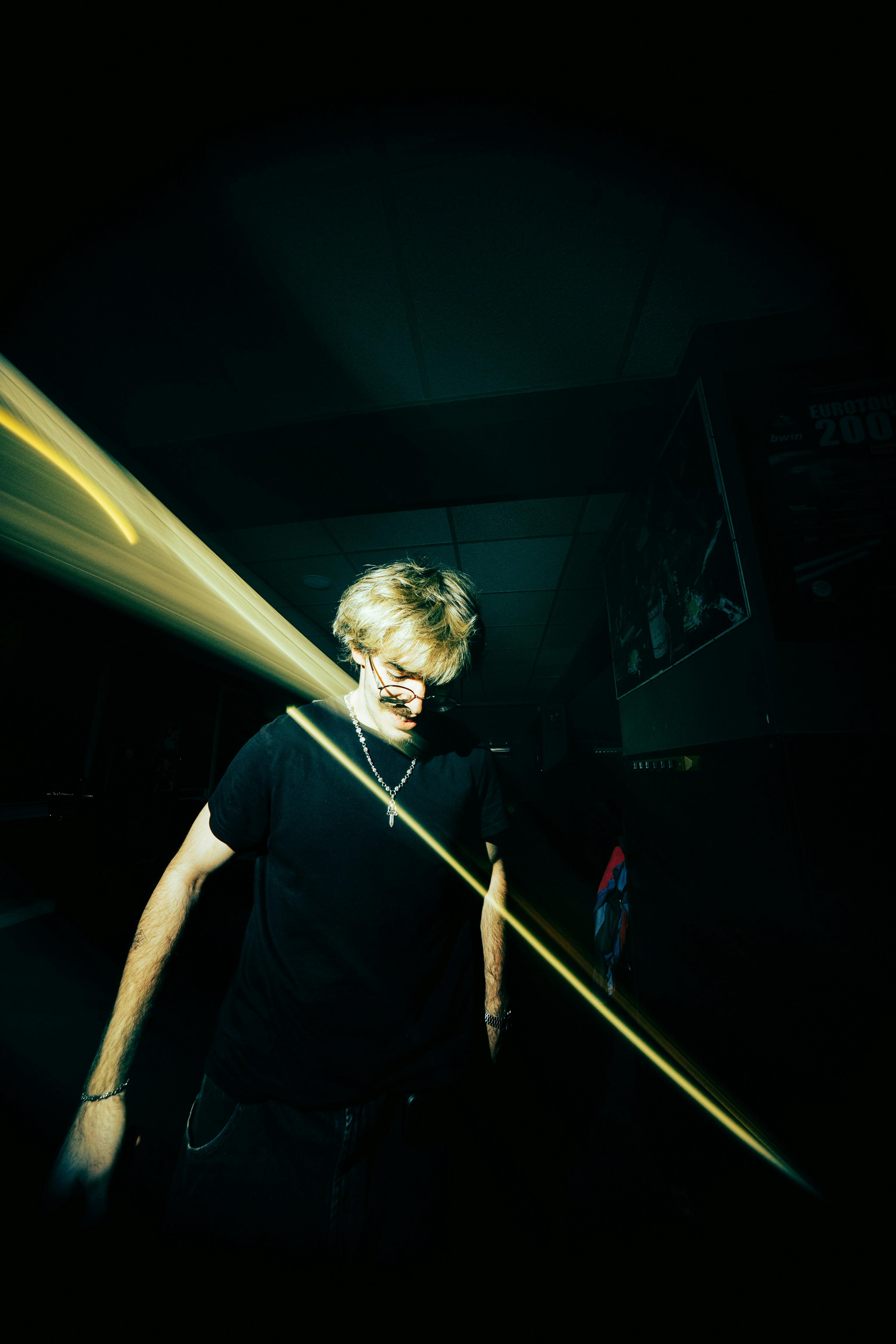 Neon Arc: A lone performer under a diagonal light trail in the dark venue