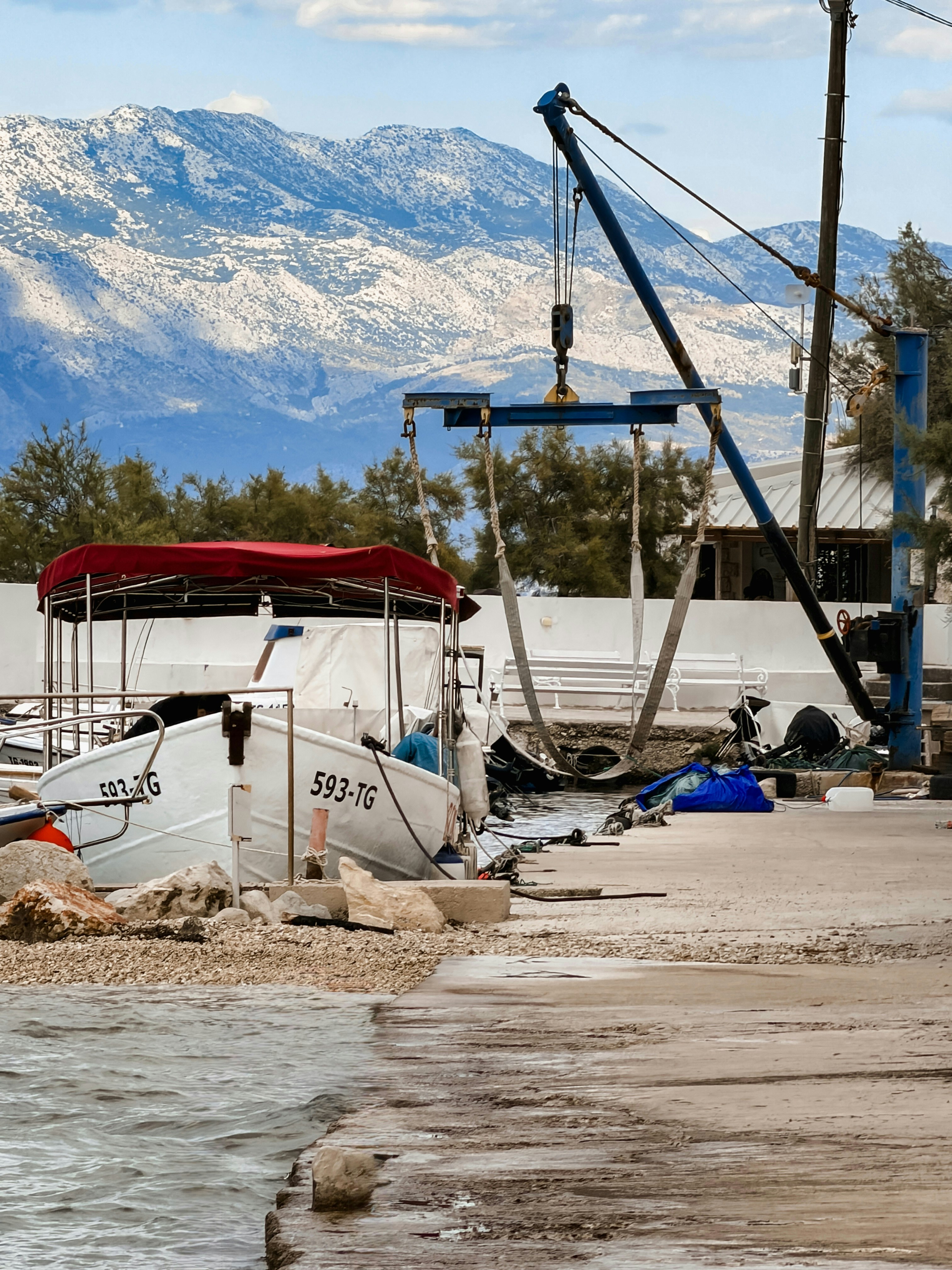 Slipstream at the Marina: Boats, Crane, and Mountain Backdrop