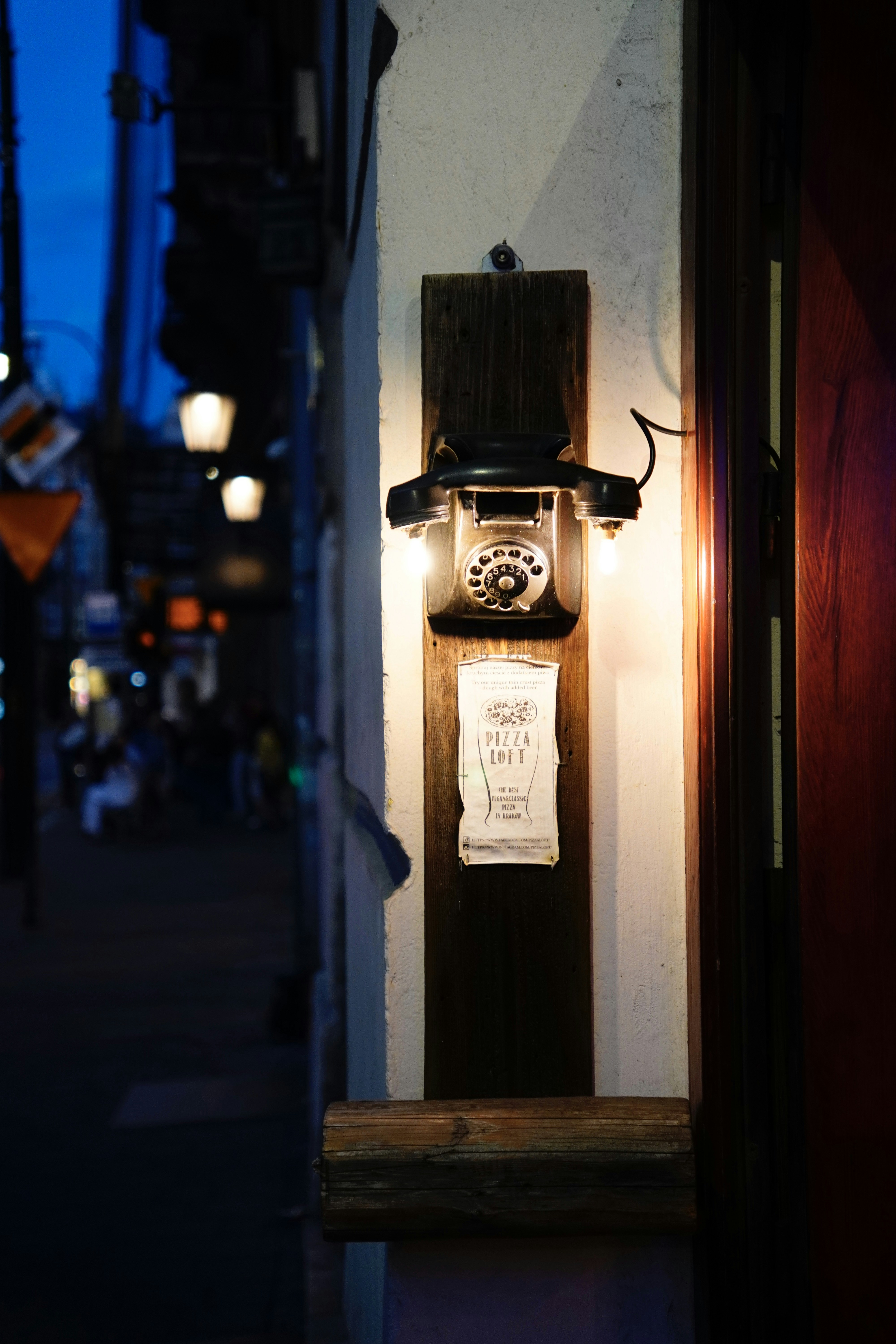 Warm Neon at the Wall: A Vintage Phone Light in a Nighttime Street