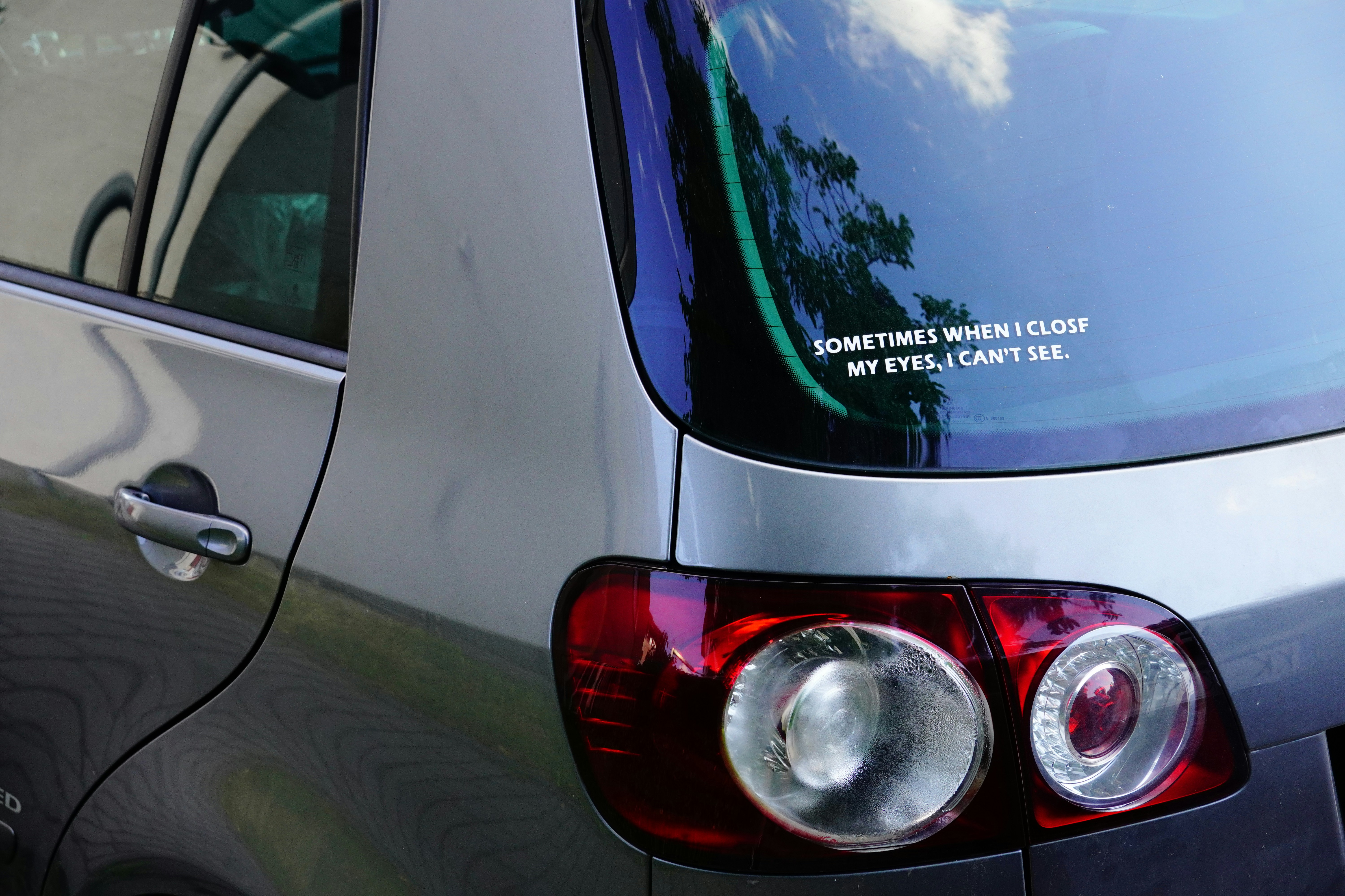 Stickered rear window: a silver hatchback with a cheeky quote