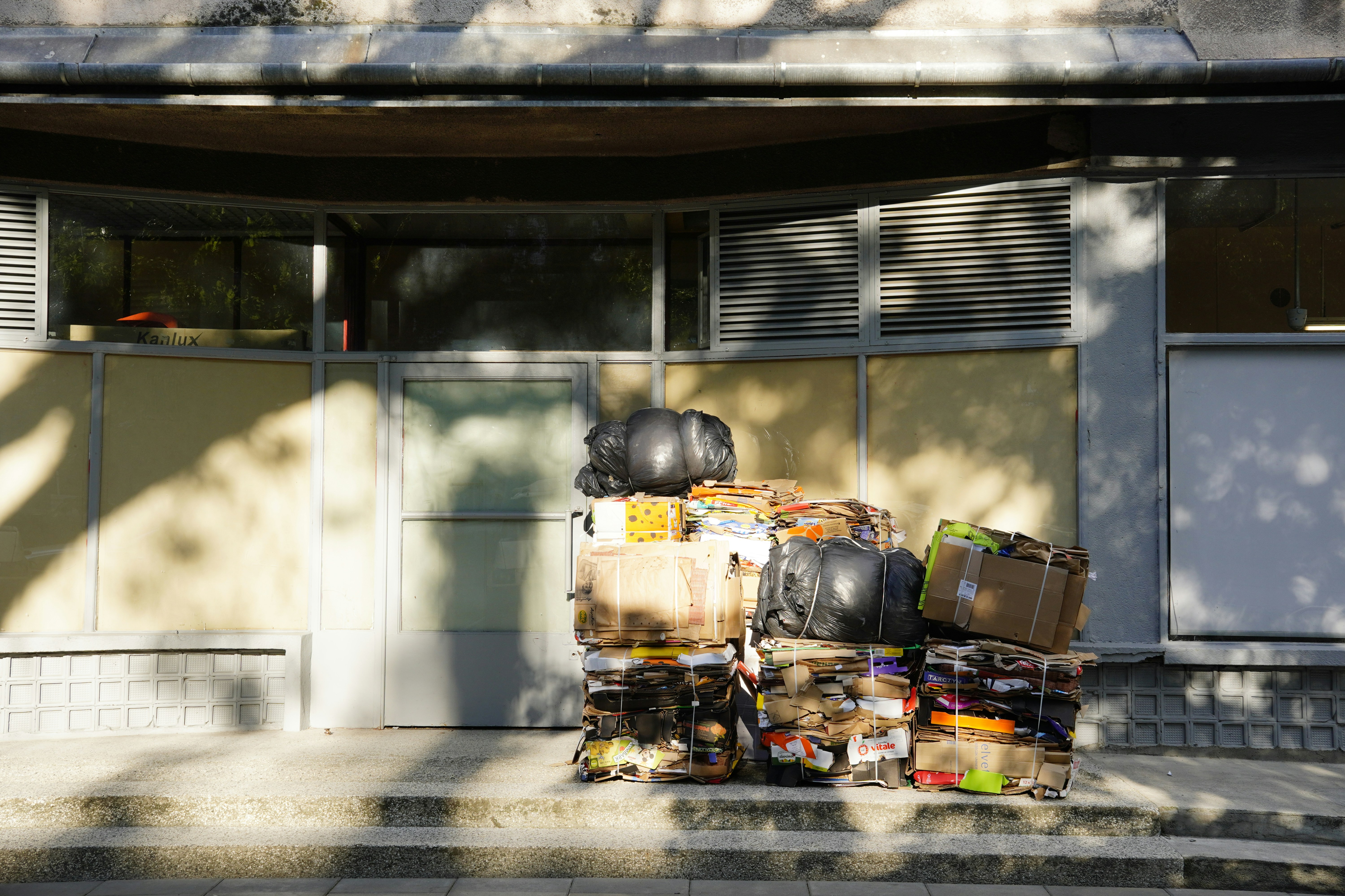 Cardboard Heap Under Schoolyard Shadow