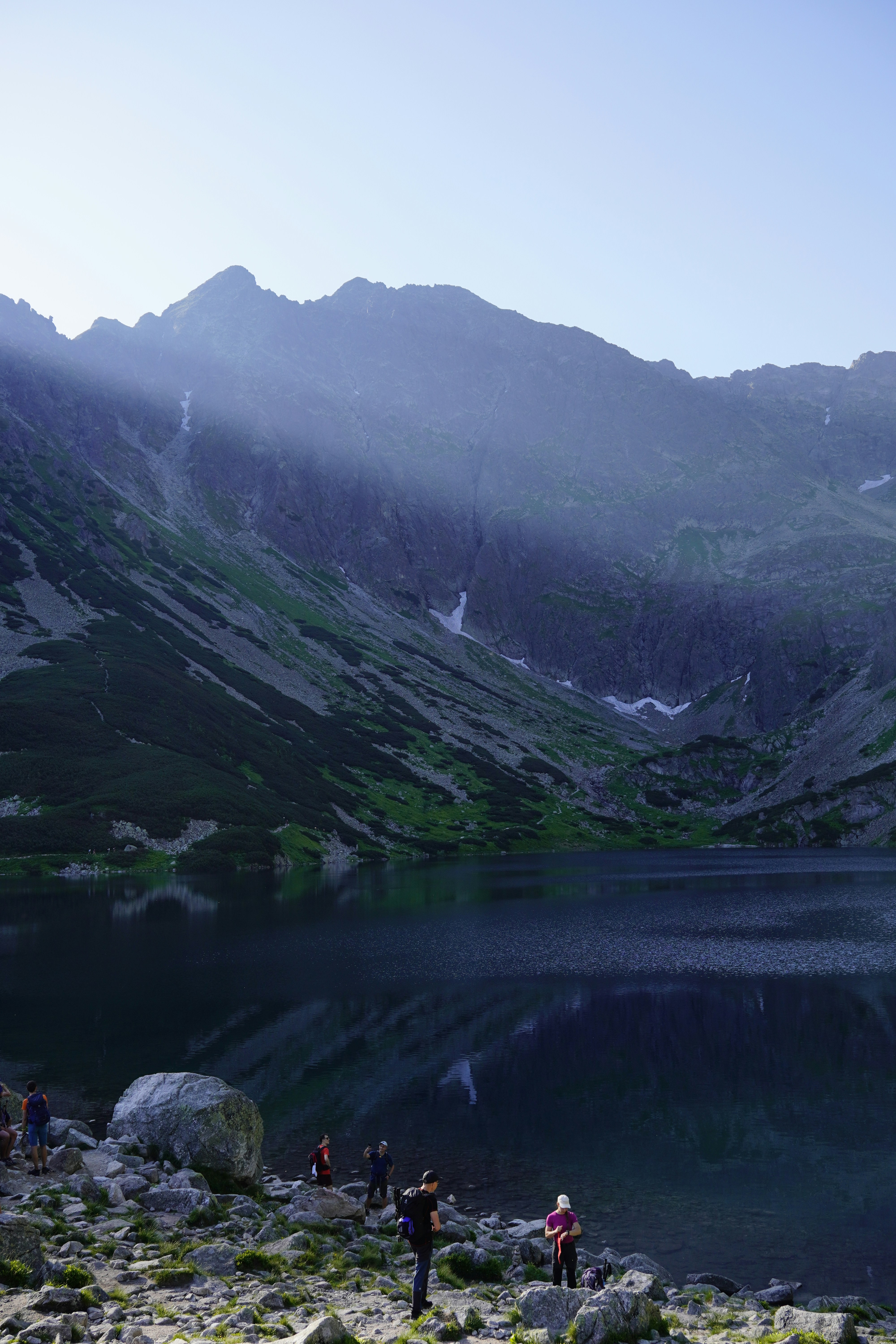 Silent Azure Basin: Hikers Converge by a Mountain Lake