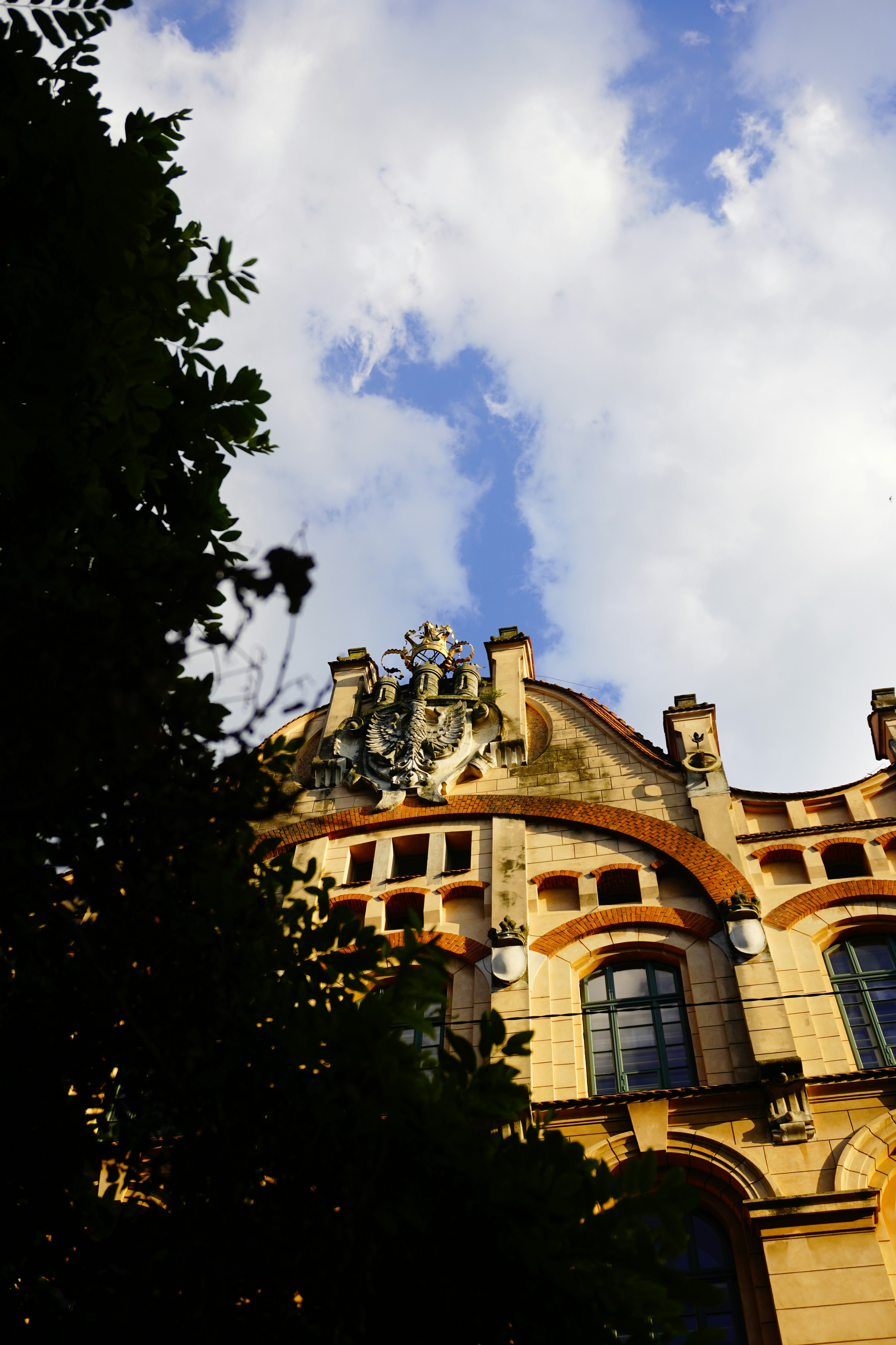 Architectural Crest: A historic facade peeking through foliage beneath dramatic sky