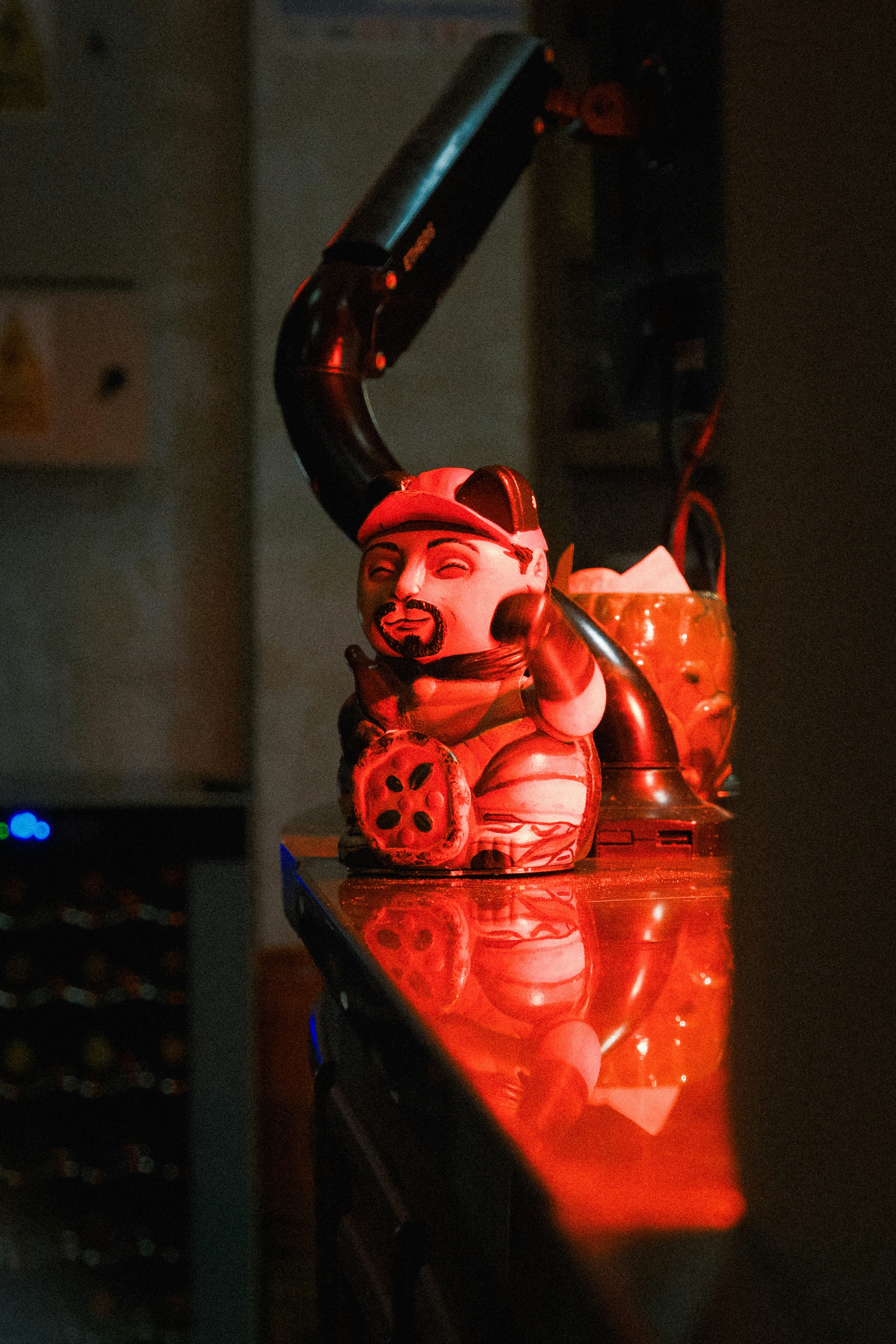 Red Lucky Figurine on a Reflective Bar Counter Under Warm Neon