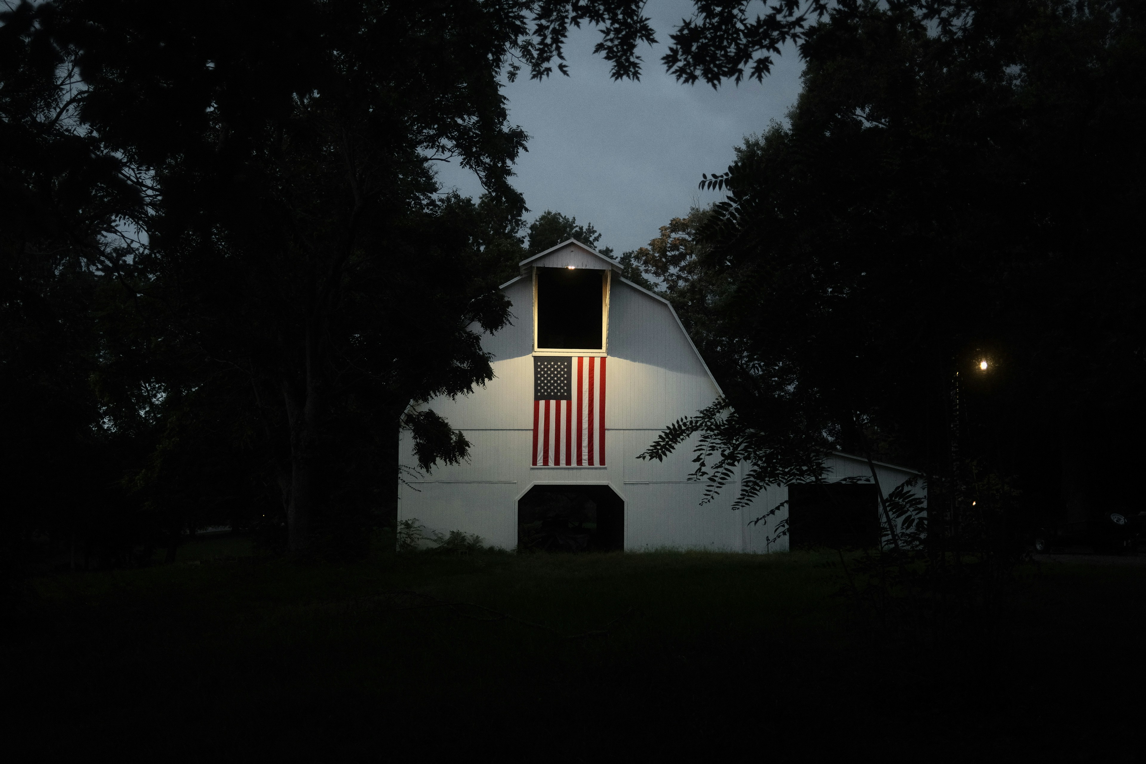 American Barn at Dusk: A Flaglit Facade Amid Dense Shadows