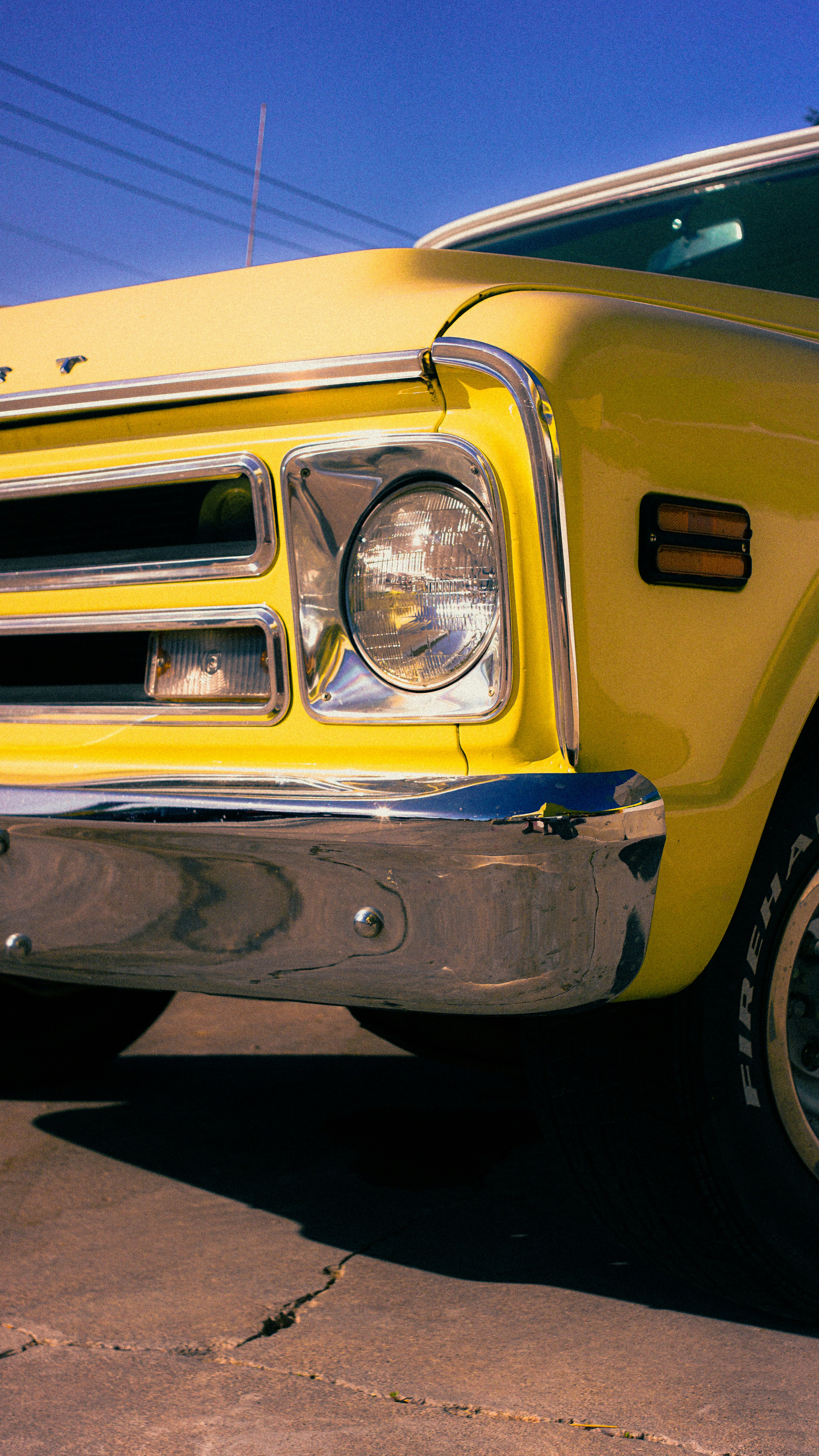 Chrome-and-yellow: the front quarter of a vintage truck under a cloudless blue sky