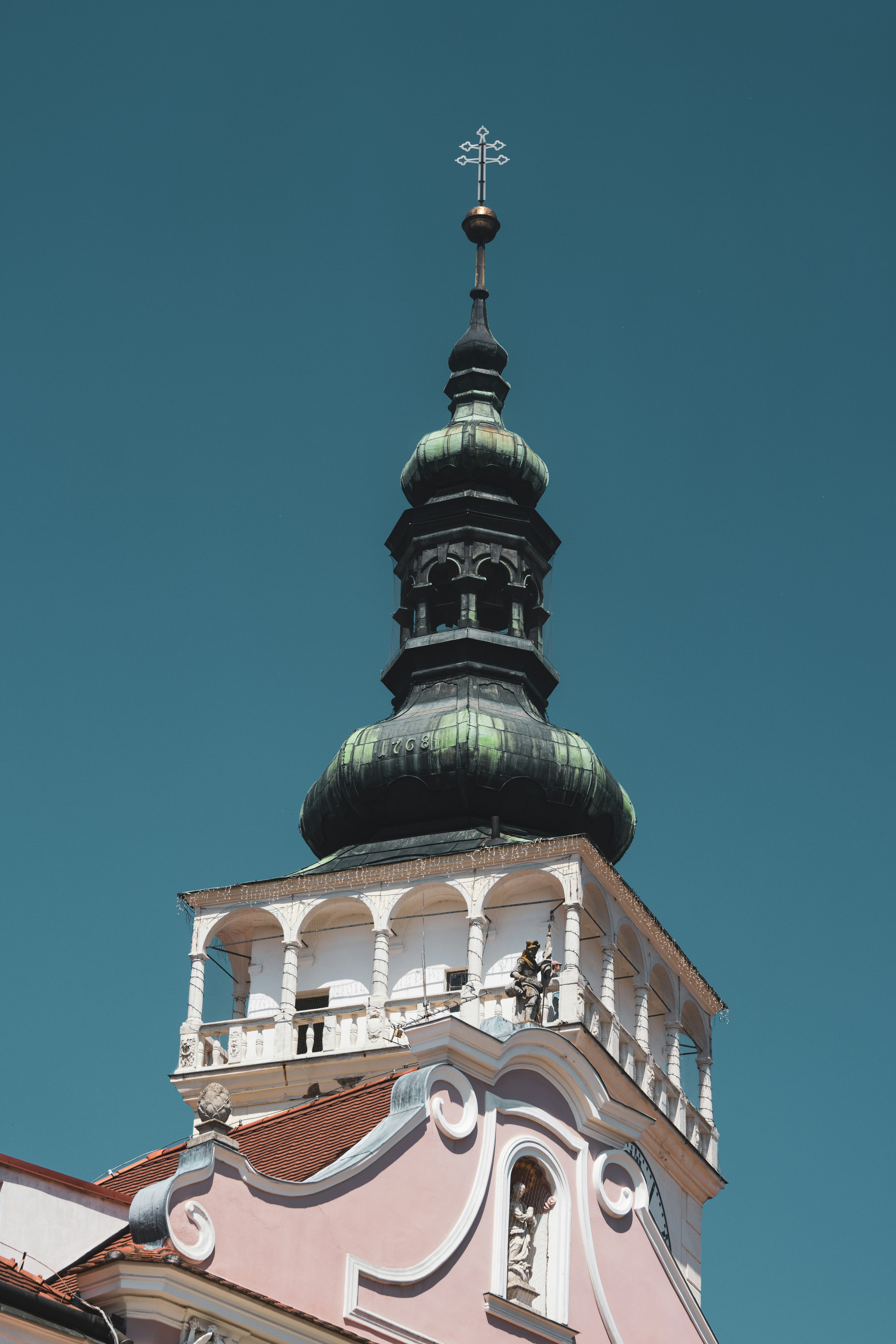 Bell tower rising over pastel façade against a clear blue sky