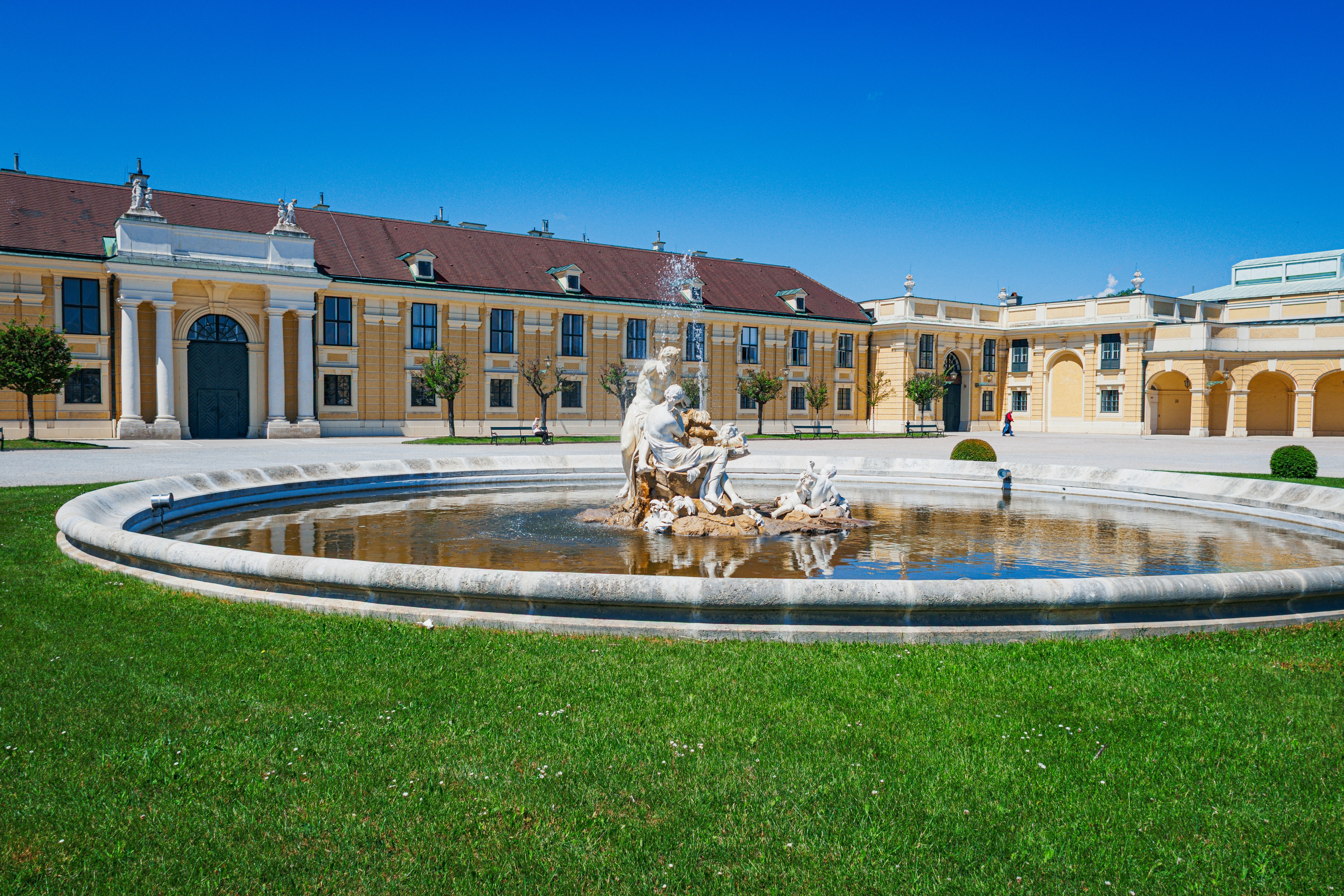 Symmetrical Courtyard Fountain: Classical Statues in a Sunlit Arc