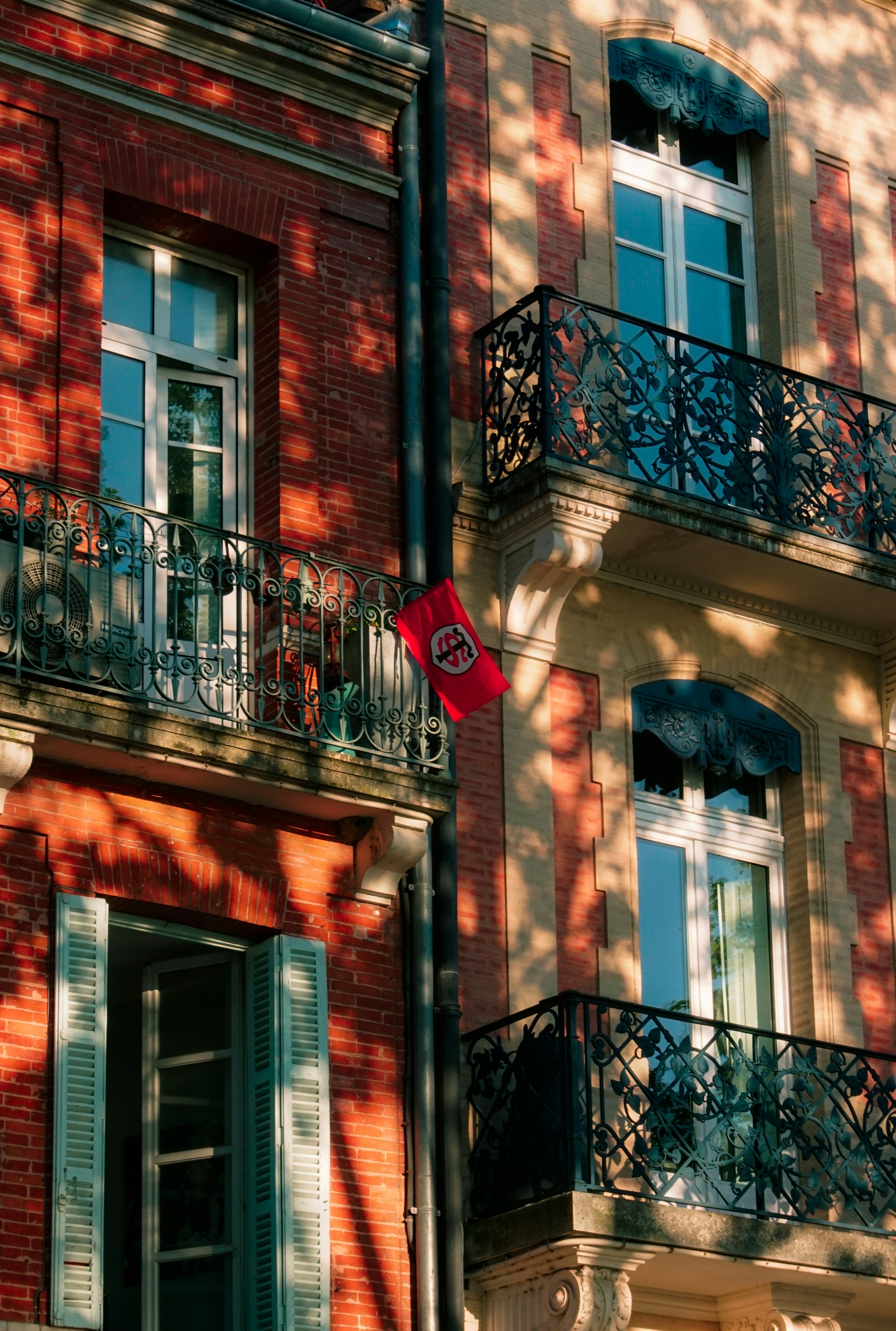 Red Facade, Shaded Balcony: A Sun-Dappling Urban Facade