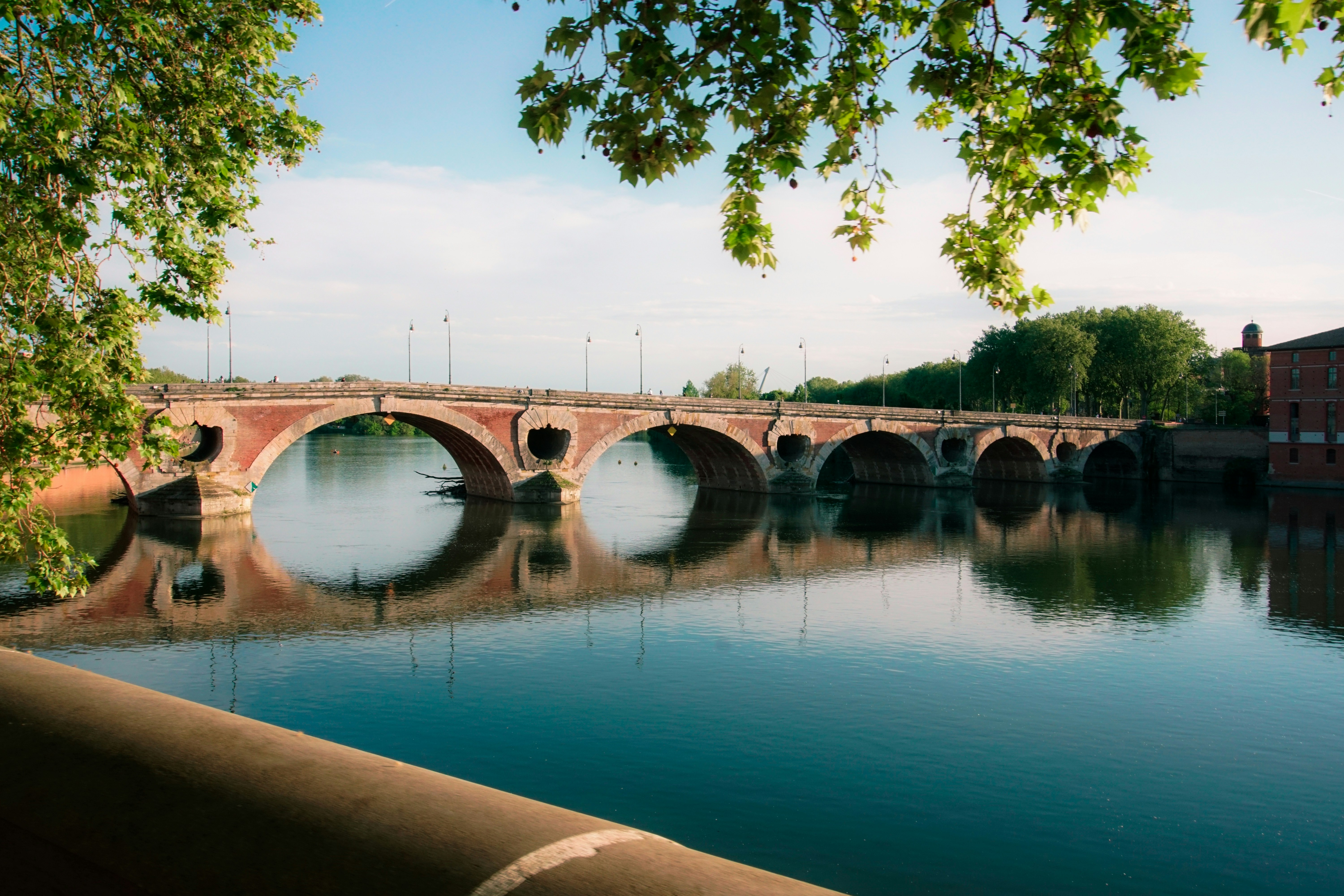 Arched Bridge Mirrored: A Quiet Riverside Across the Sunlit Water